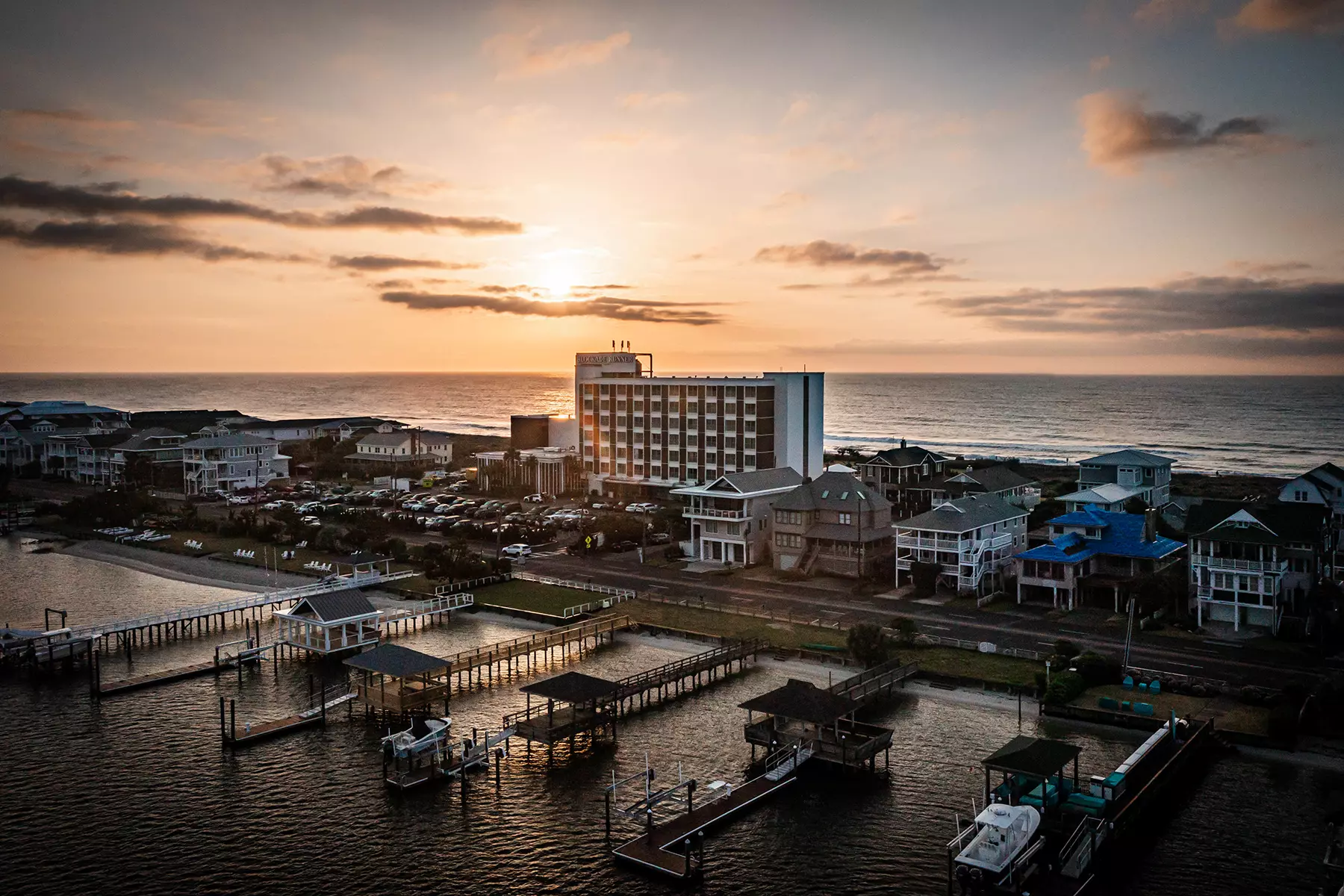 La puesta de sol con edificios y muelles entre la bahía y la costa en Blockade Runner Resort en Wilmington