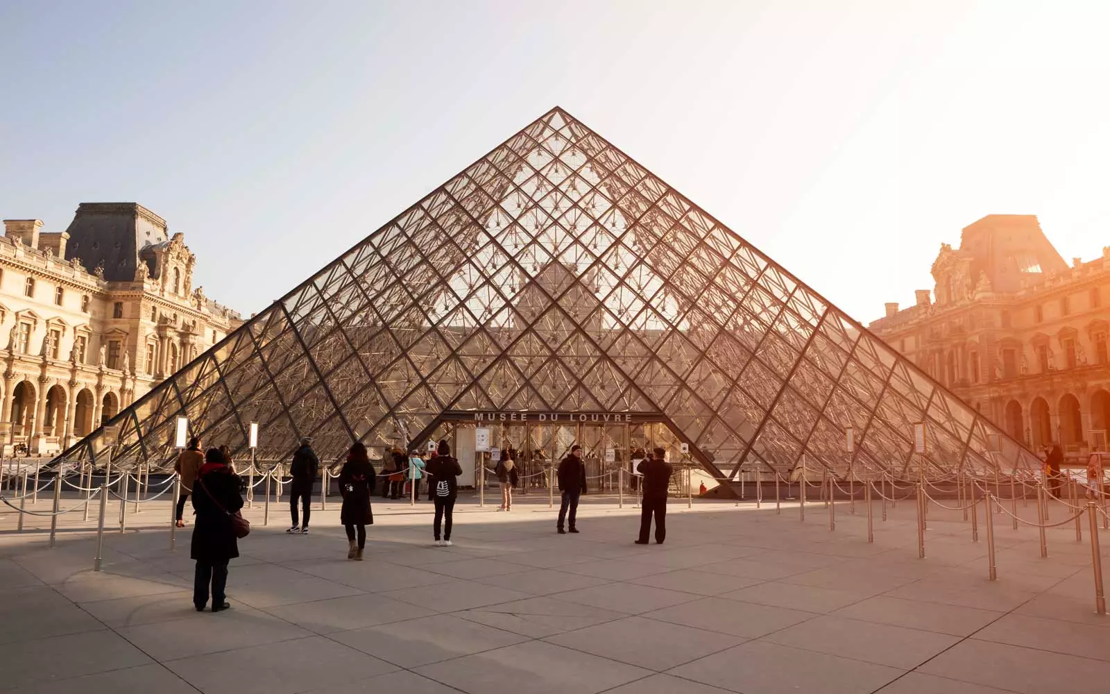 Turister går nær glaspyramide i Louvre-paladsets gårdhave, Paris, Frankrig