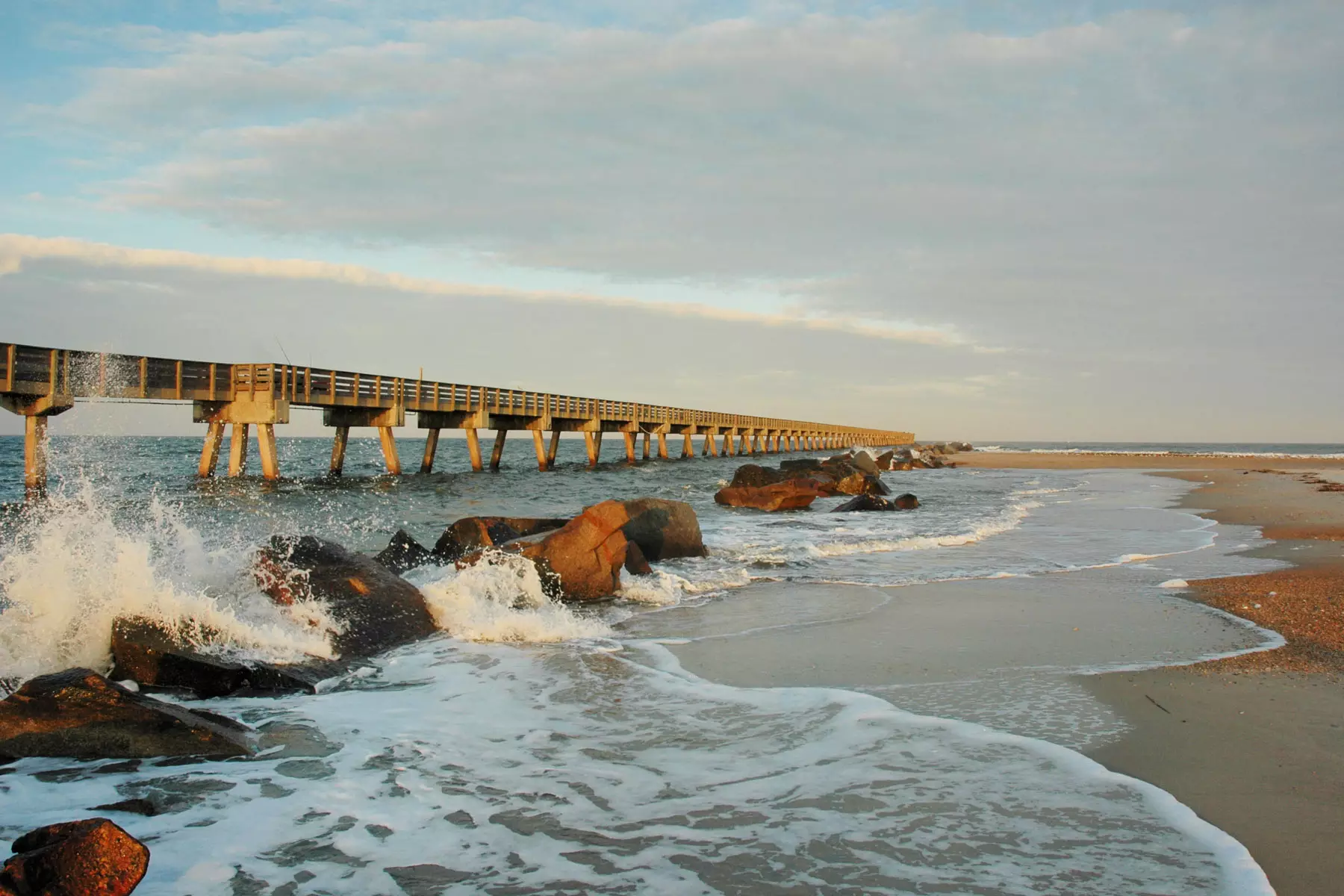 Ondas quebrando contra ondas ao longo do píer no extremo norte de Amelia Island, Flórida