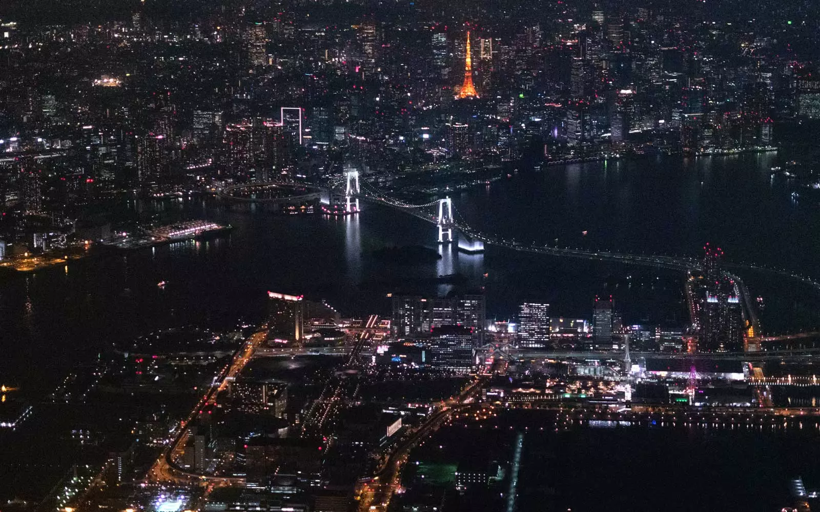 Das Foto wurde vom Verkehrsflugzeug Tokyo Haneda International Airport (HND) zum Akita Airpot (AXT) aufgenommen. Der obere rot beleuchtete Turm ist der Tokyo Tower und die linke Hängebrücke ist die Rainbow Bridge.