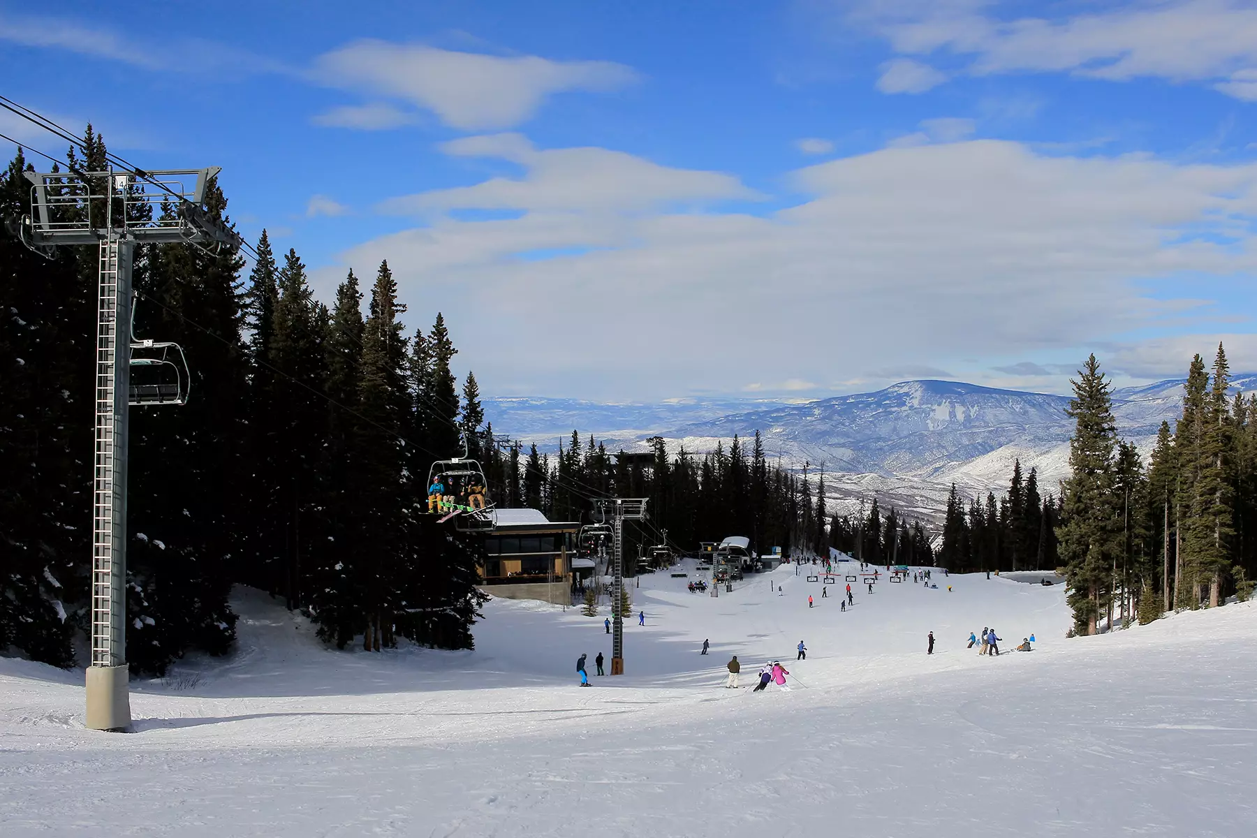 Skiers lan snowboarders ski mudhun kanggo chairlift ing Snowmass