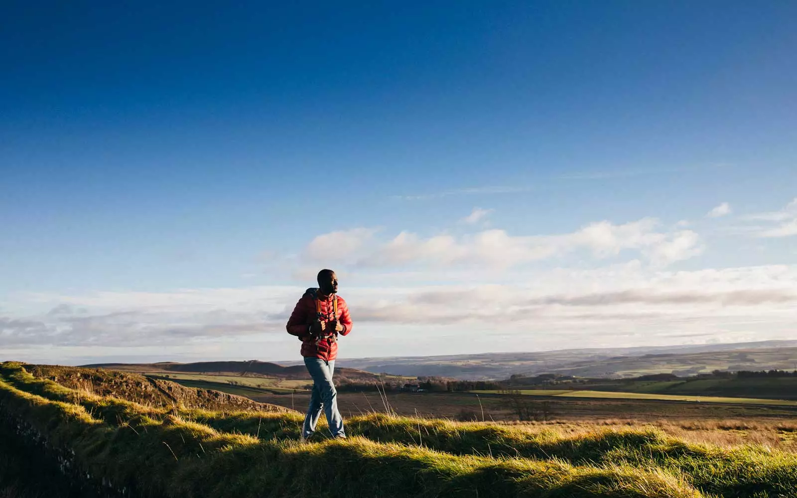 Un tânăr adult care se plimbă pe Zidul lui Hadrian în Northumberland, Marea Britanie.