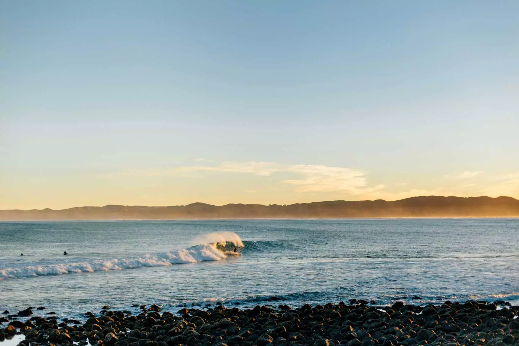 Navega por Manu Bay ao amencer. Manu Bay (tamén coñecida como The Point) é unha zona de surf de fama mundial. Está a uns seis km ao sur de Raglan.