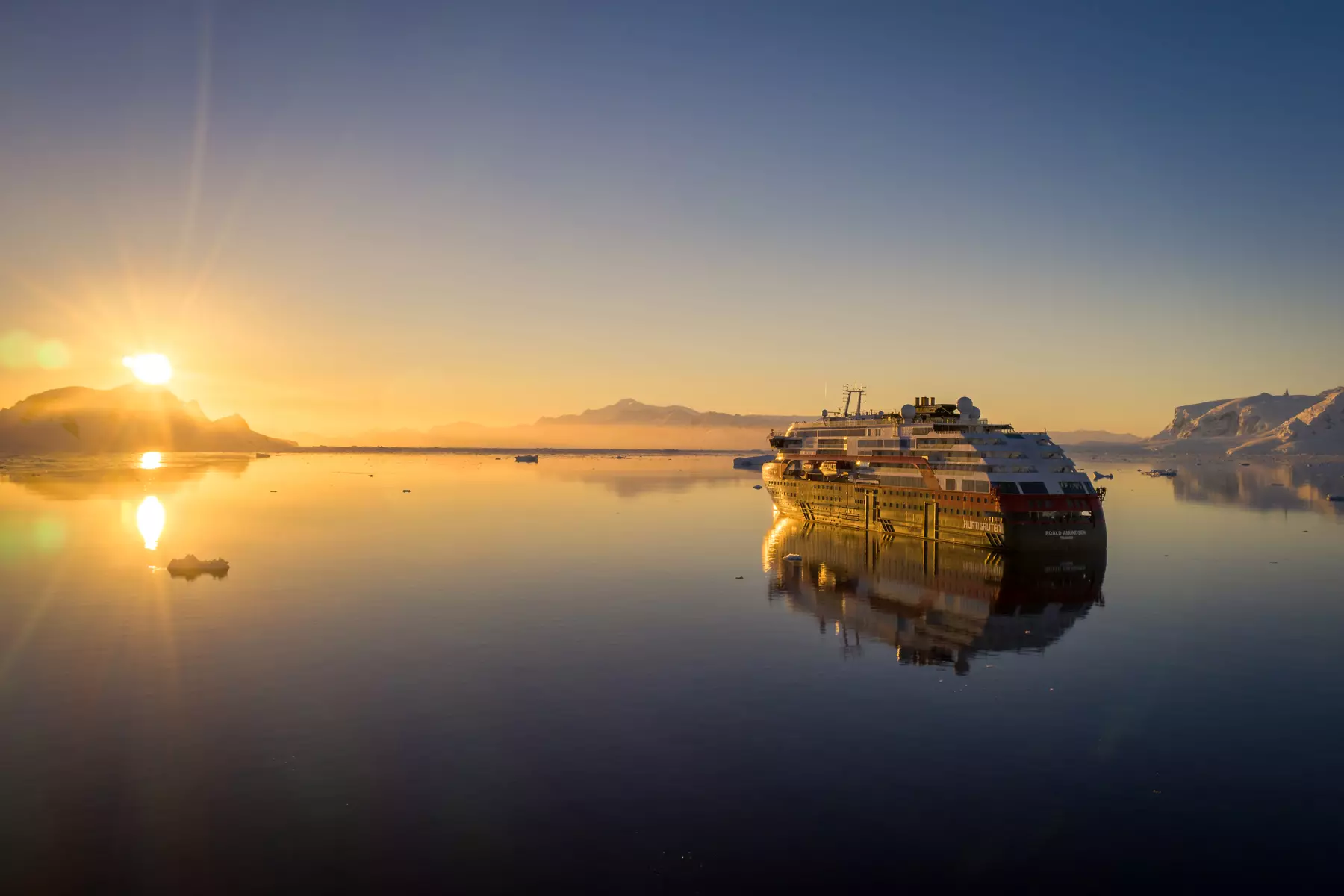 Maliit na cruise ship sa salamin na makinis na tubig na nakatingin sa araw