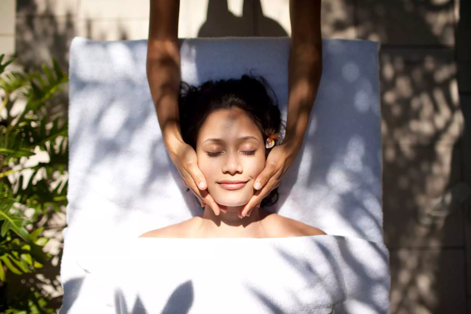 Donna che ottiene un trattamento di bellezza per il viso con massaggio tropicale in una spa
