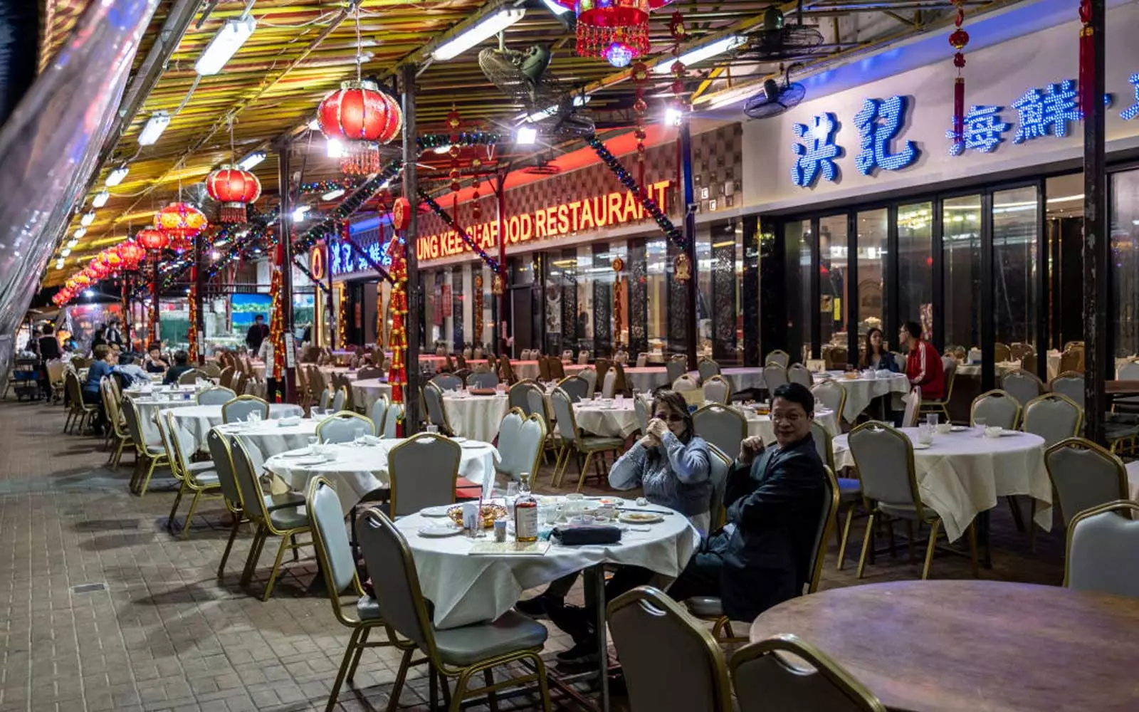 Un uomo e una donna sono seduti a un tavolo all'interno di un ristorante all'aperto il 27 febbraio 2020 a Hong Kong, Cina