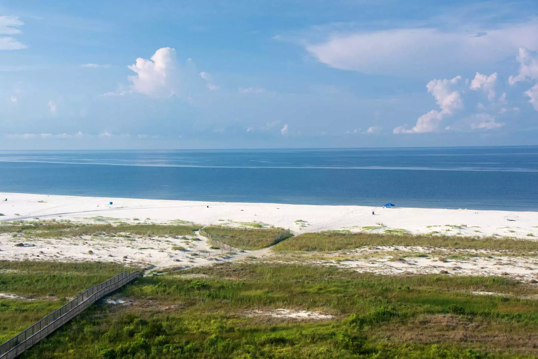 View ayeryen sou litoral plaj ak boardwalk sou Dauphin Island nan Alabama nan yon jou solèy ble syèl.