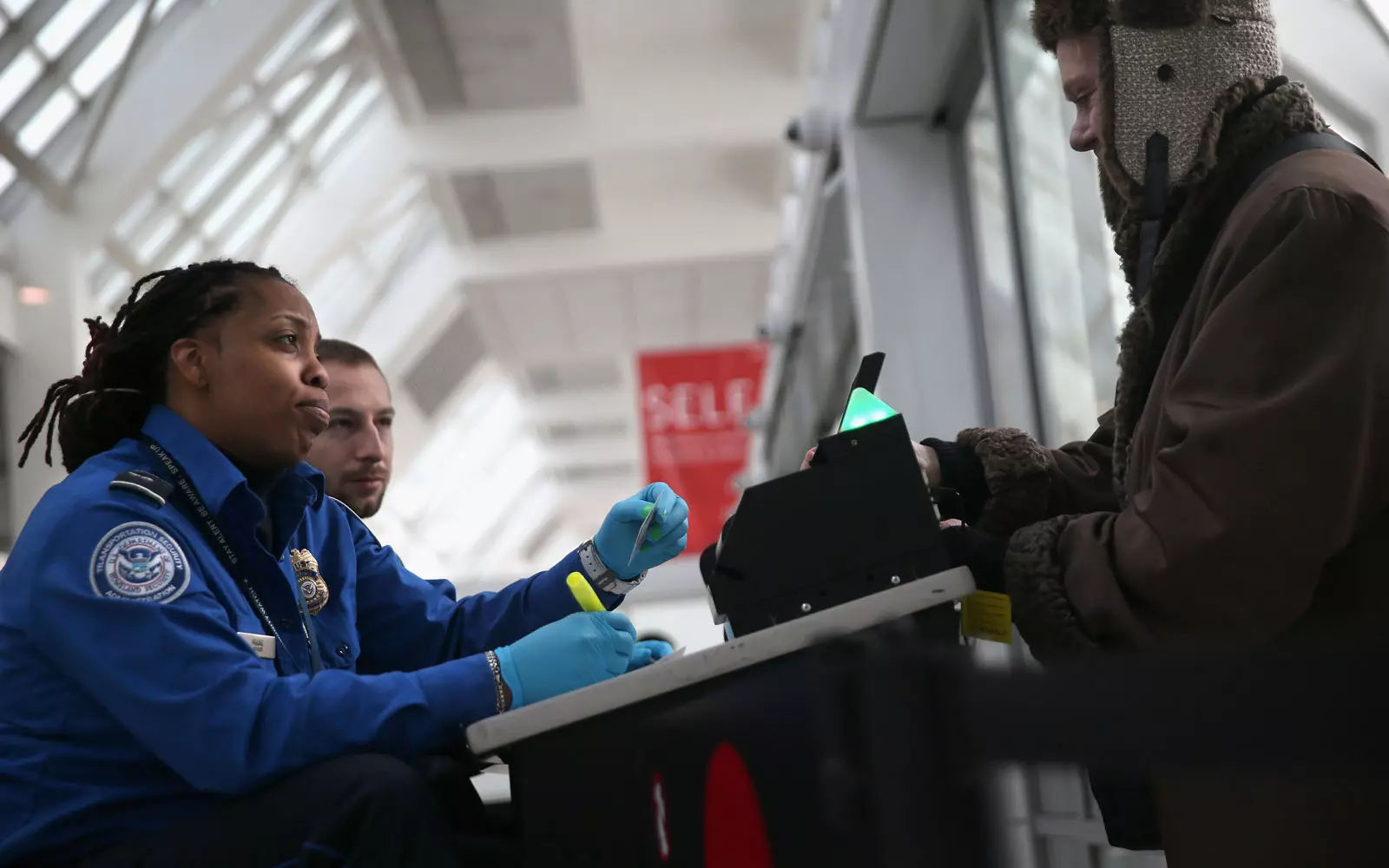 Agent TSA kontroluje cestovní průkaz na bezpečnostní kontrole