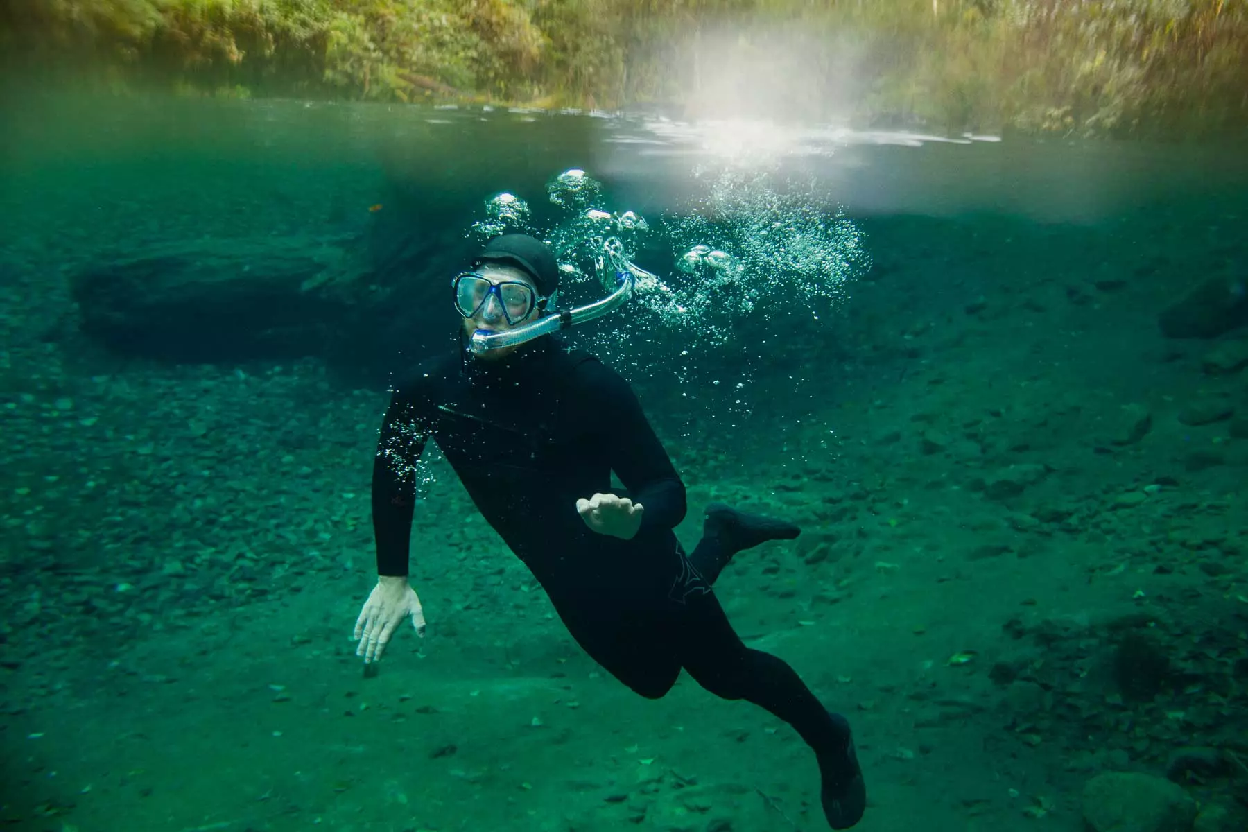 Gizon bat neoprenoz jantzita eta snorkela Kanadako erreka batean