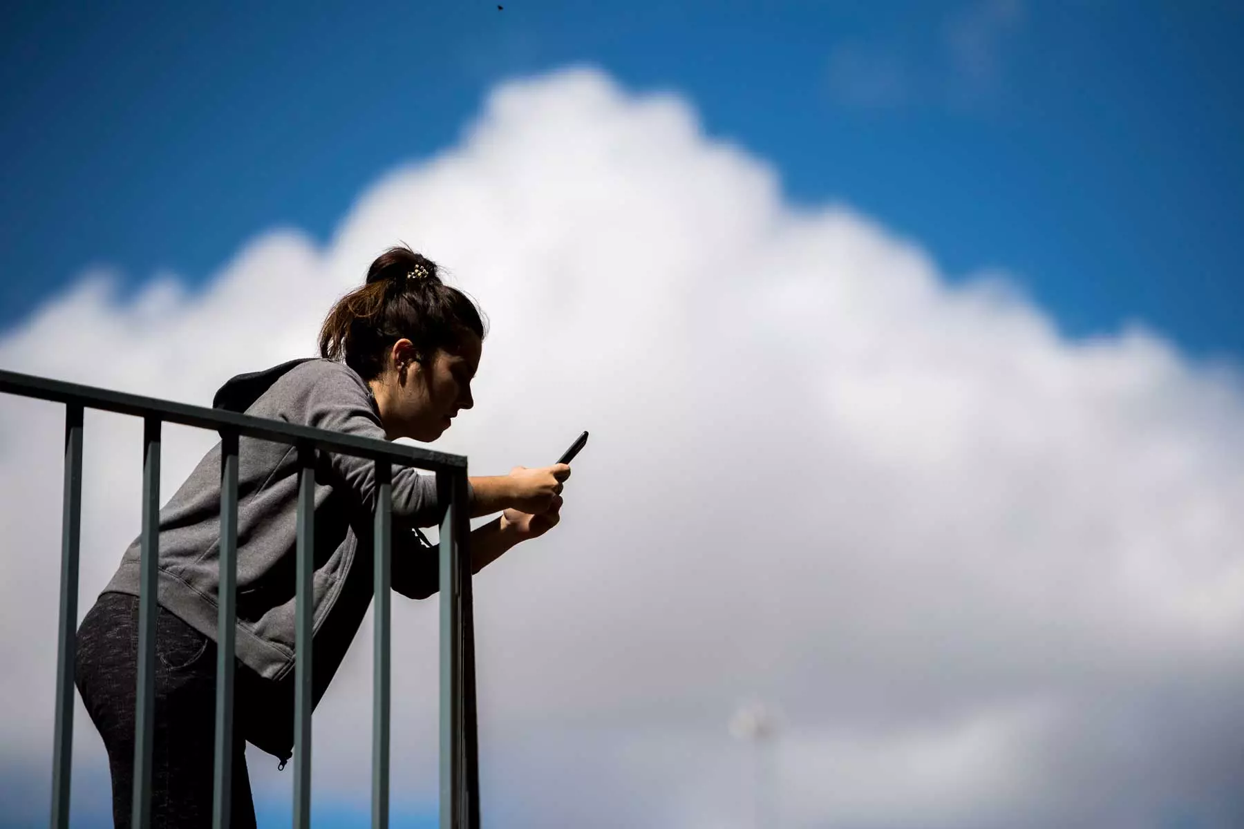 Eine Frau benutzt ihr Smartphone auf dem Balkon ihres Hauses