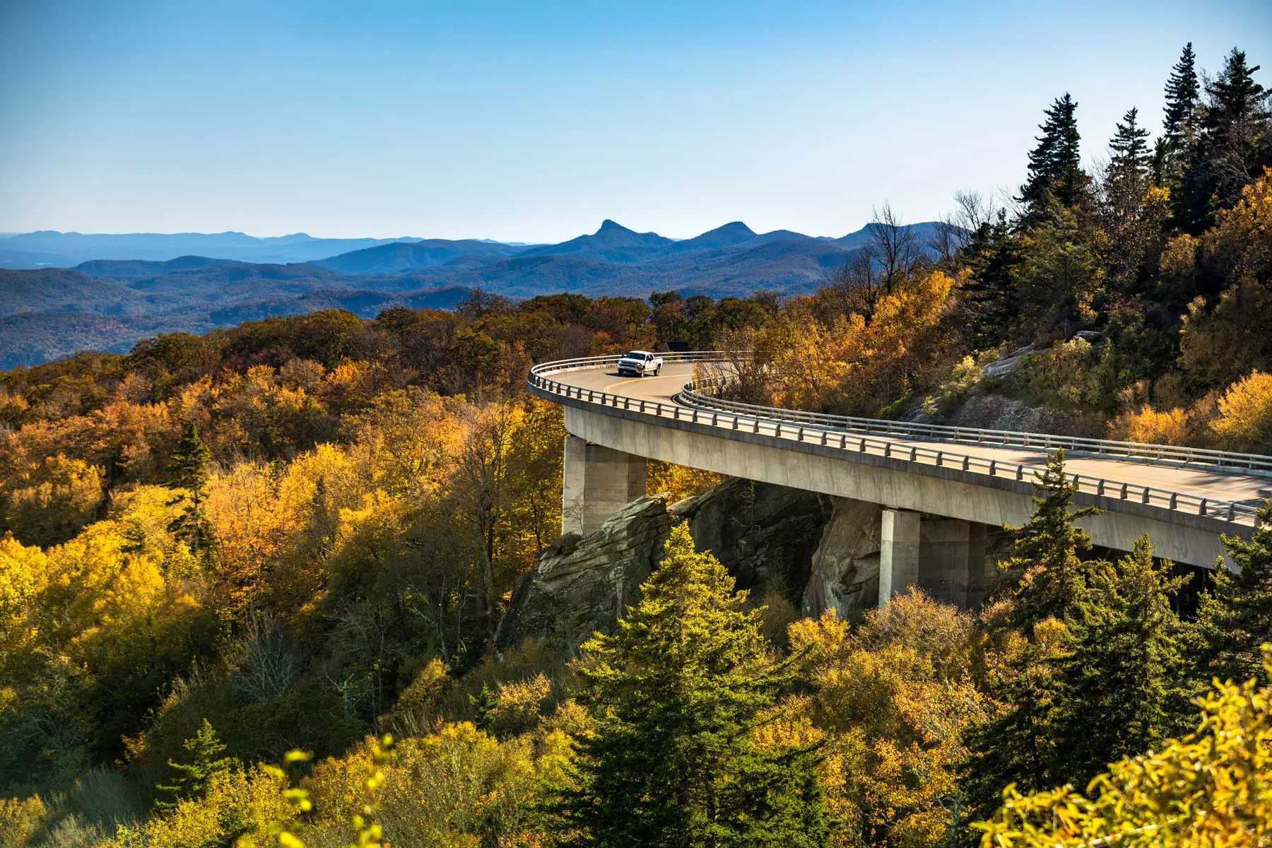 ဆောင်းဦးပေါက်မြောက်ကာရိုလိုင်းနားရှိ Blue Ridge Parkway တစ်လျှောက်ရှိ Grandfather Mountain ရှိ Linn Cove Viaduct အဝေးပြေးလမ်းမကြီးပေါ်တွင် ကားများ သွားလာနေသည်