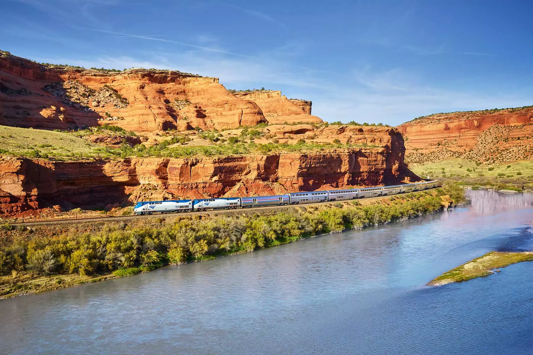 Një tren Amtrak, Zephyr, kalon nëpër luginën e shkretëtirës përgjatë një lumi në Kaliforni