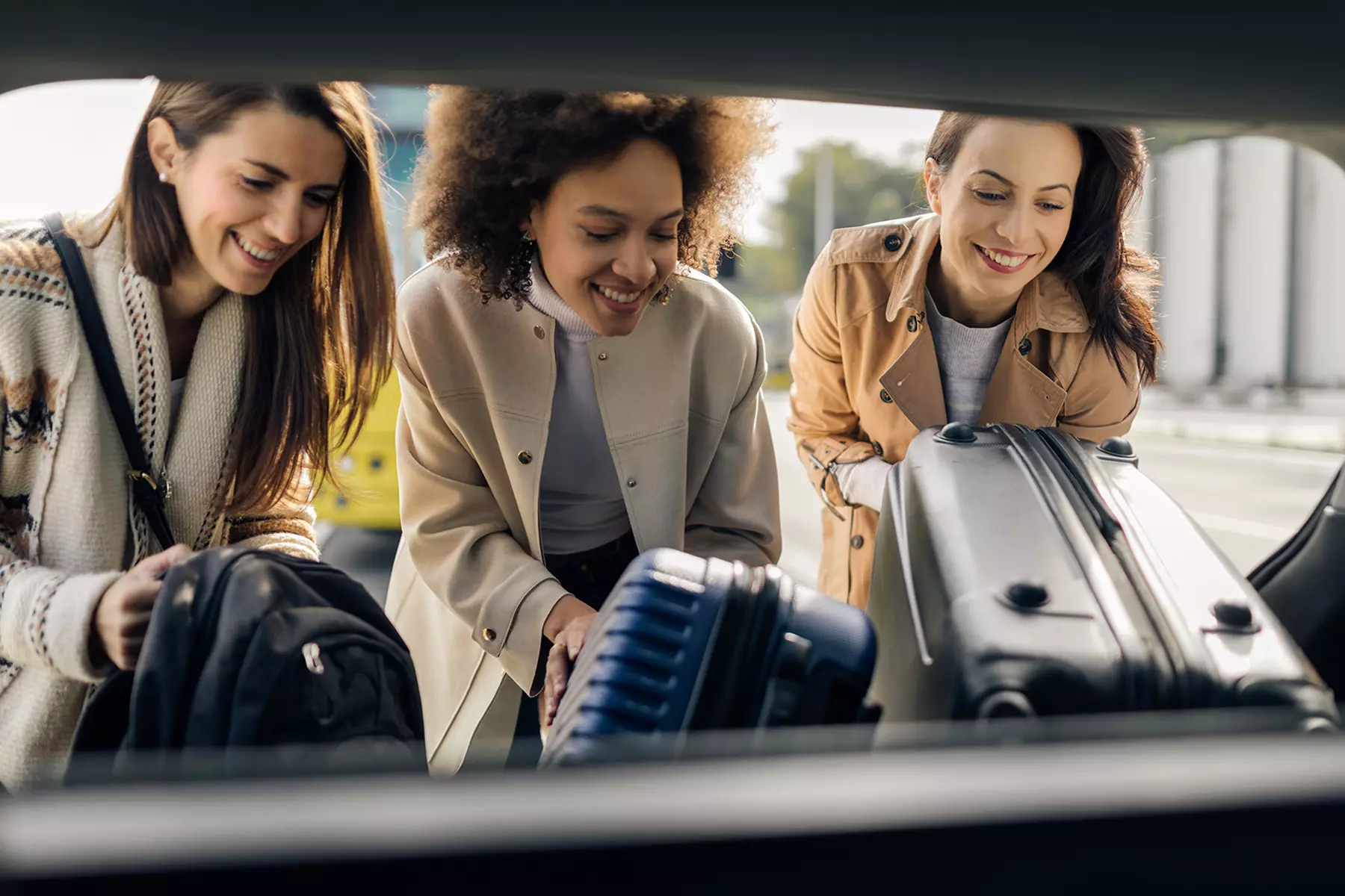 Três amigos viajam juntos e colocam malas no porta-malas do carro