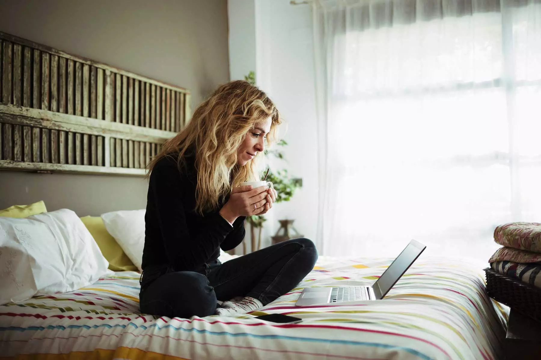 Vrouw met behulp van laptopcomputer zittend op bed thuis