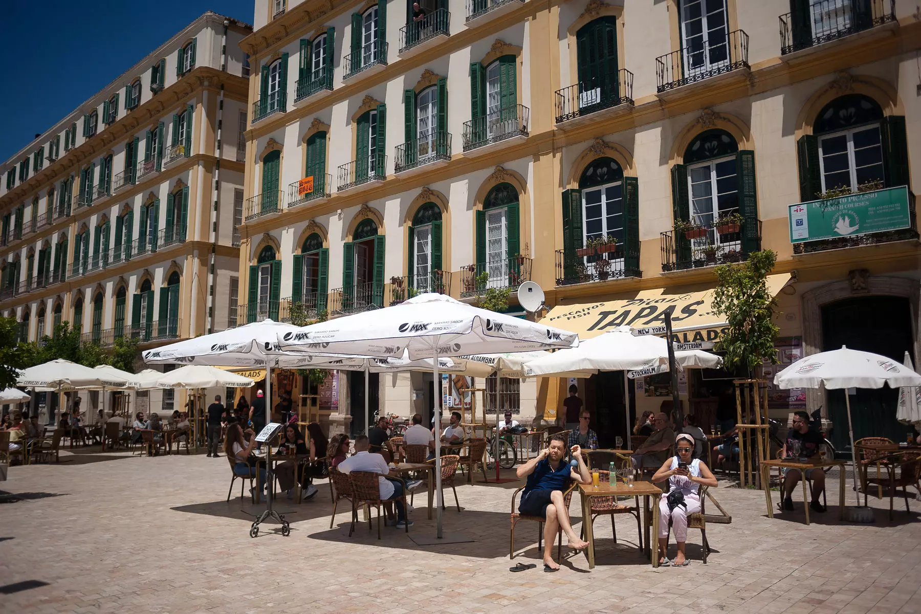 Menschen sitzen in Spanien draußen an Esstischen