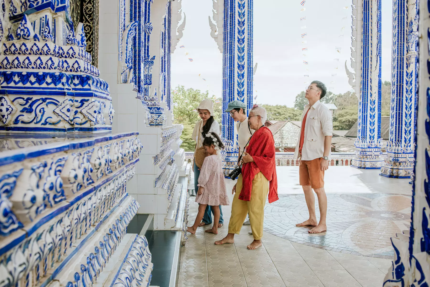 Kvinne forteller en historie om dette eldgamle thailandske tempelet til sine barnebarn, svigerdatter og sønnen hennes