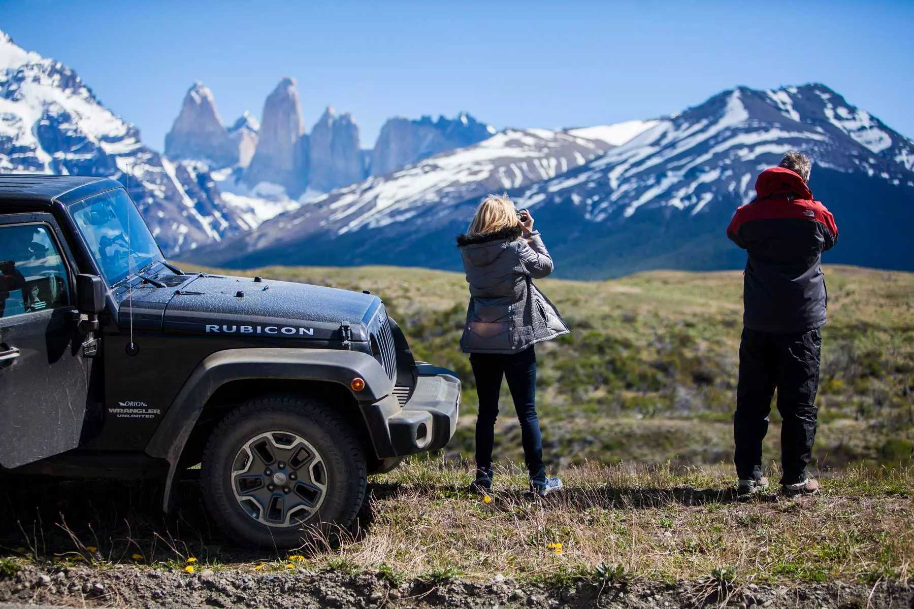 Yon koup kanpe bò yon Jeep pandan y ap foto Twa Towers yo, nan Patagonia