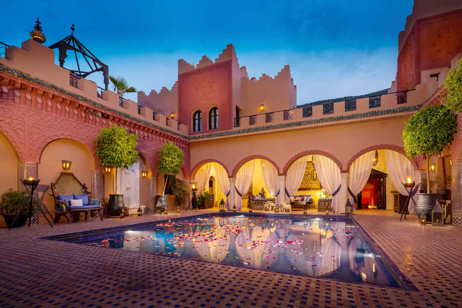 Piscina reflectante llena de pétalos de rosa en el resort Kasbah Tamadot en Marruecos