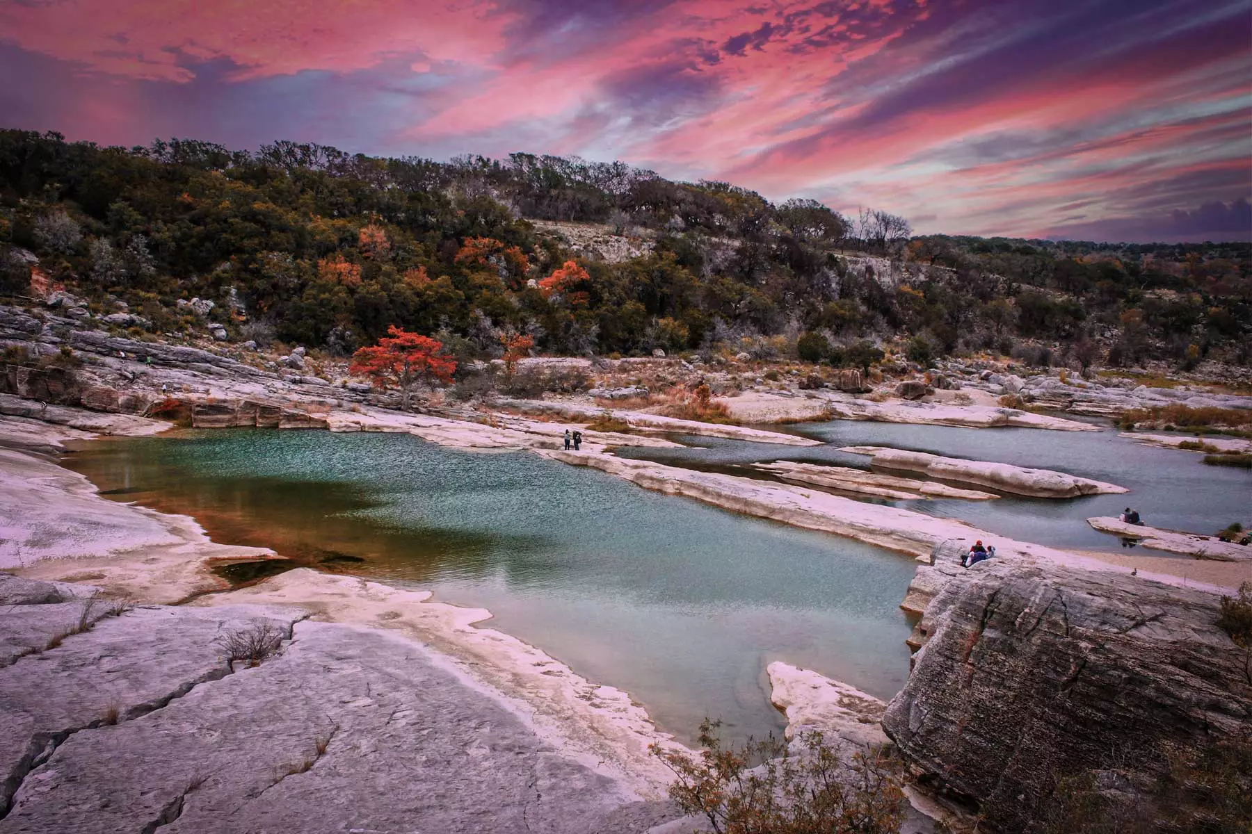 Pedernales River, der manchmal unterirdisch in der Nähe der LBJ Ranch in Teaas unter einem verrückten Sonnenuntergangshimmel mit Herbstlaub fließt