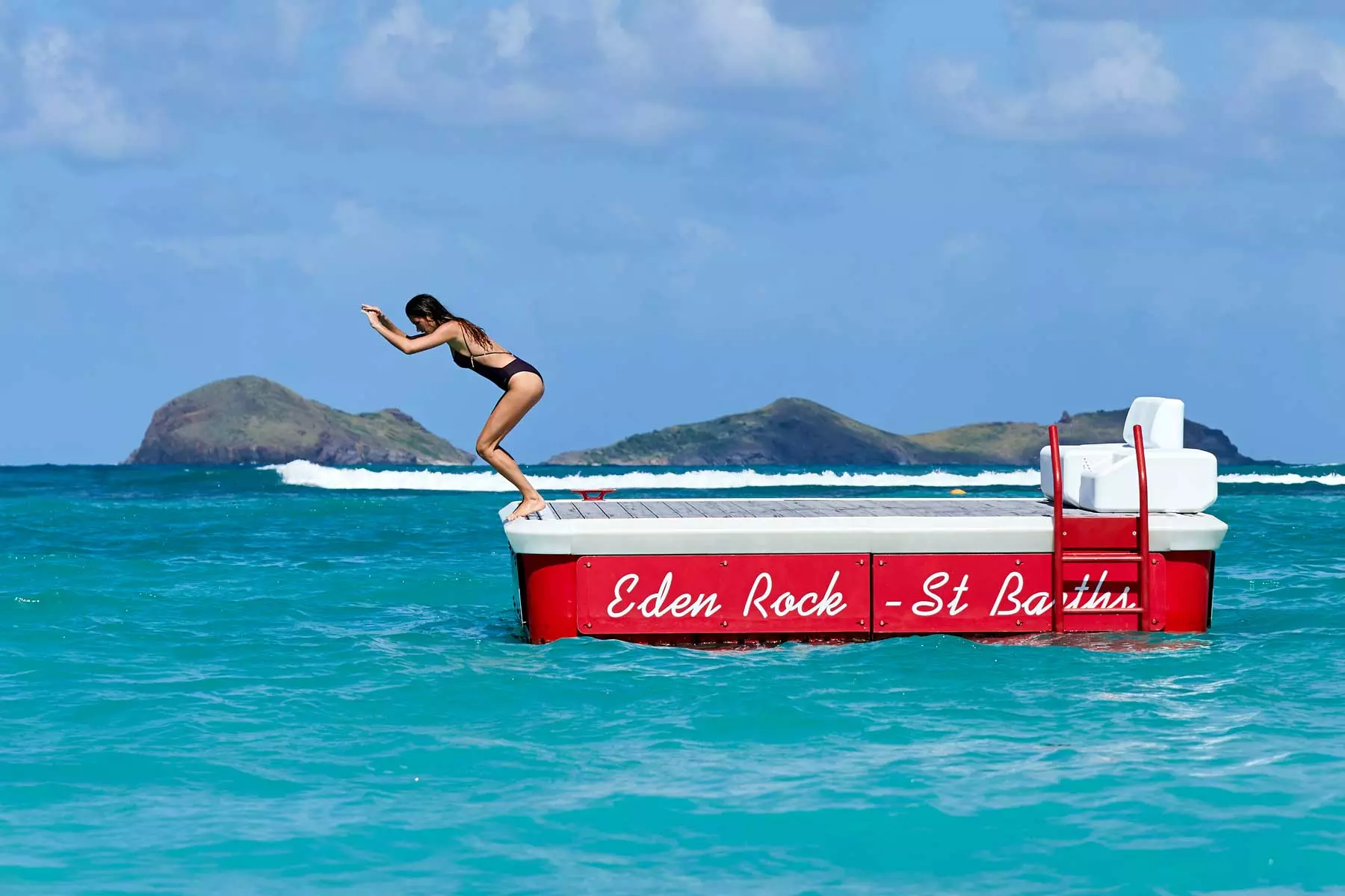 Vrou wat van 'n duikplatform afspring by Eden Rock, St Barth's