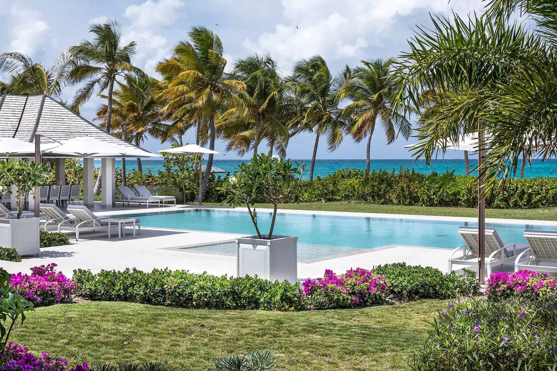 Pool omgivet af blomster og buske på feriestedet Jumby Bay i Antigua