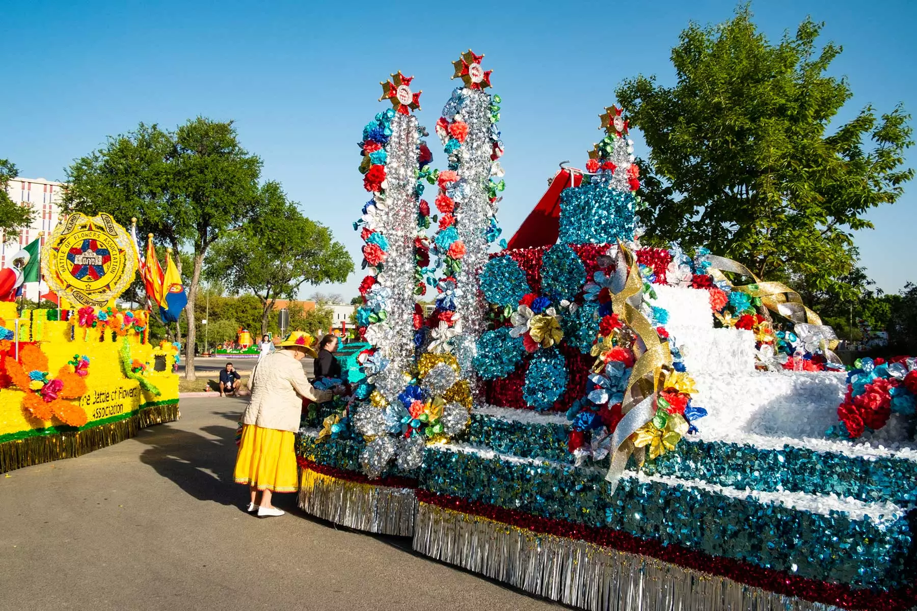 Una mujer de amarillo revisa cada centímetro de una carroza para asegurarse de que esté lista para el desfile.