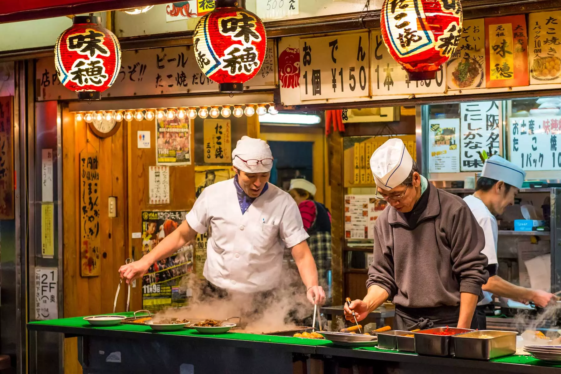 Мужчыны гатуюць традыцыйную японскую вулічную ежу ў Осацы, Японія.