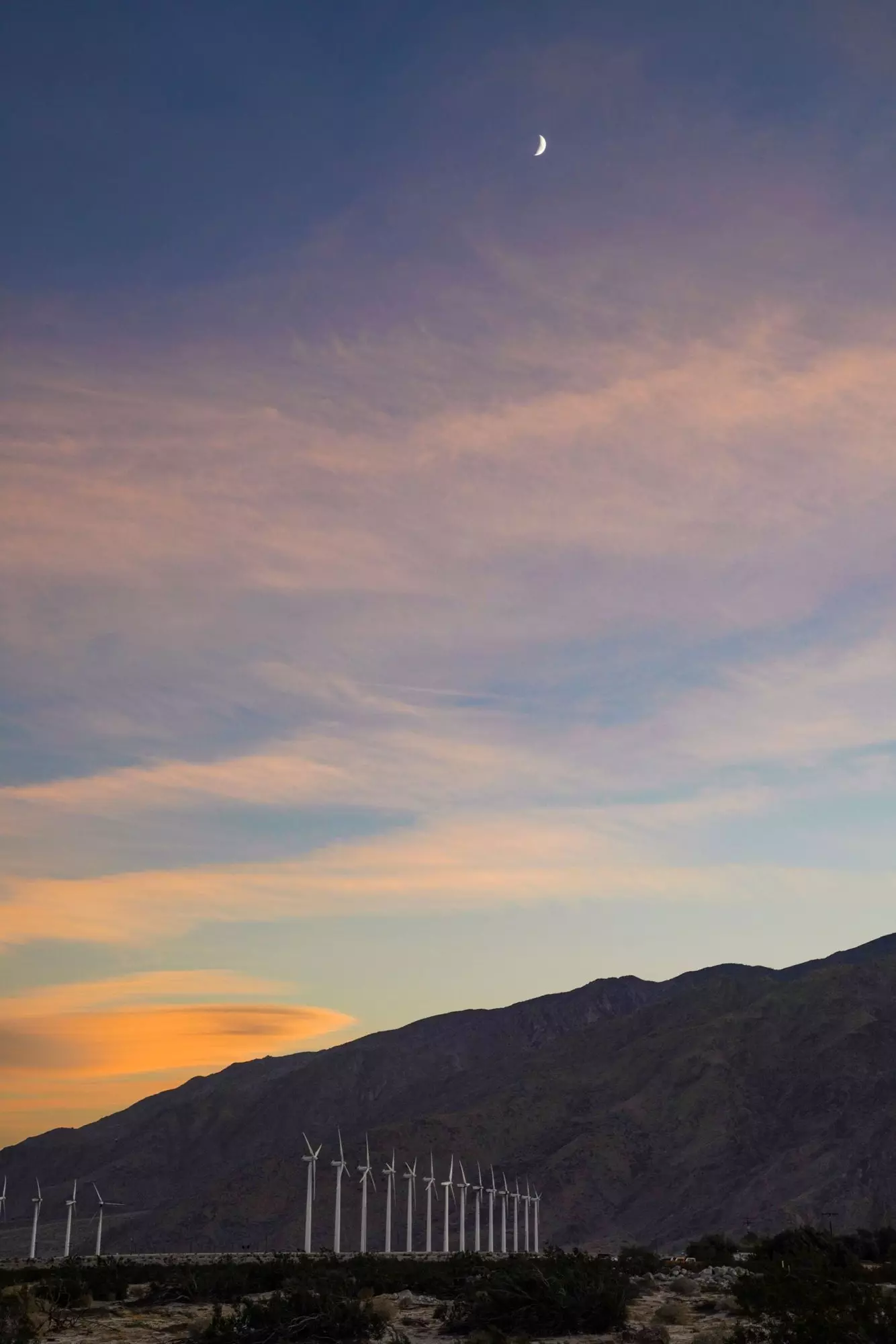 La luna se eleva sobre las montañas al atardecer desde Windmill Farms en Palm Springs