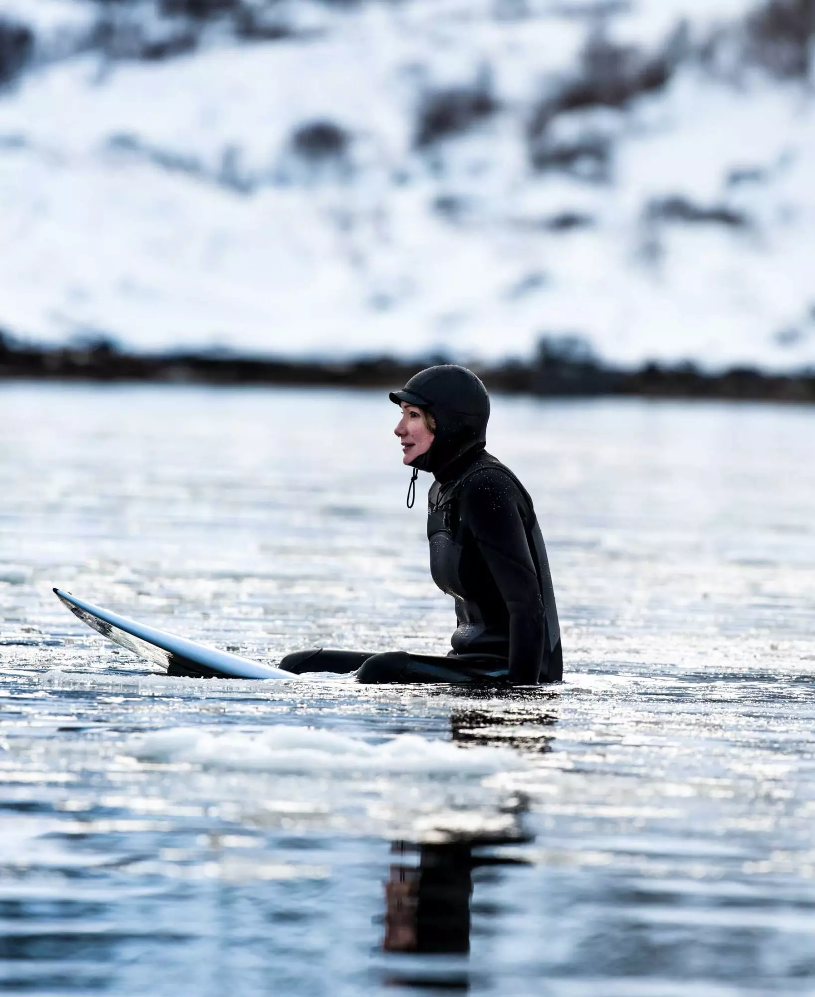 Devi Kroell i en våtdräkt på en surfbräda på Lofotenöarna, Norge