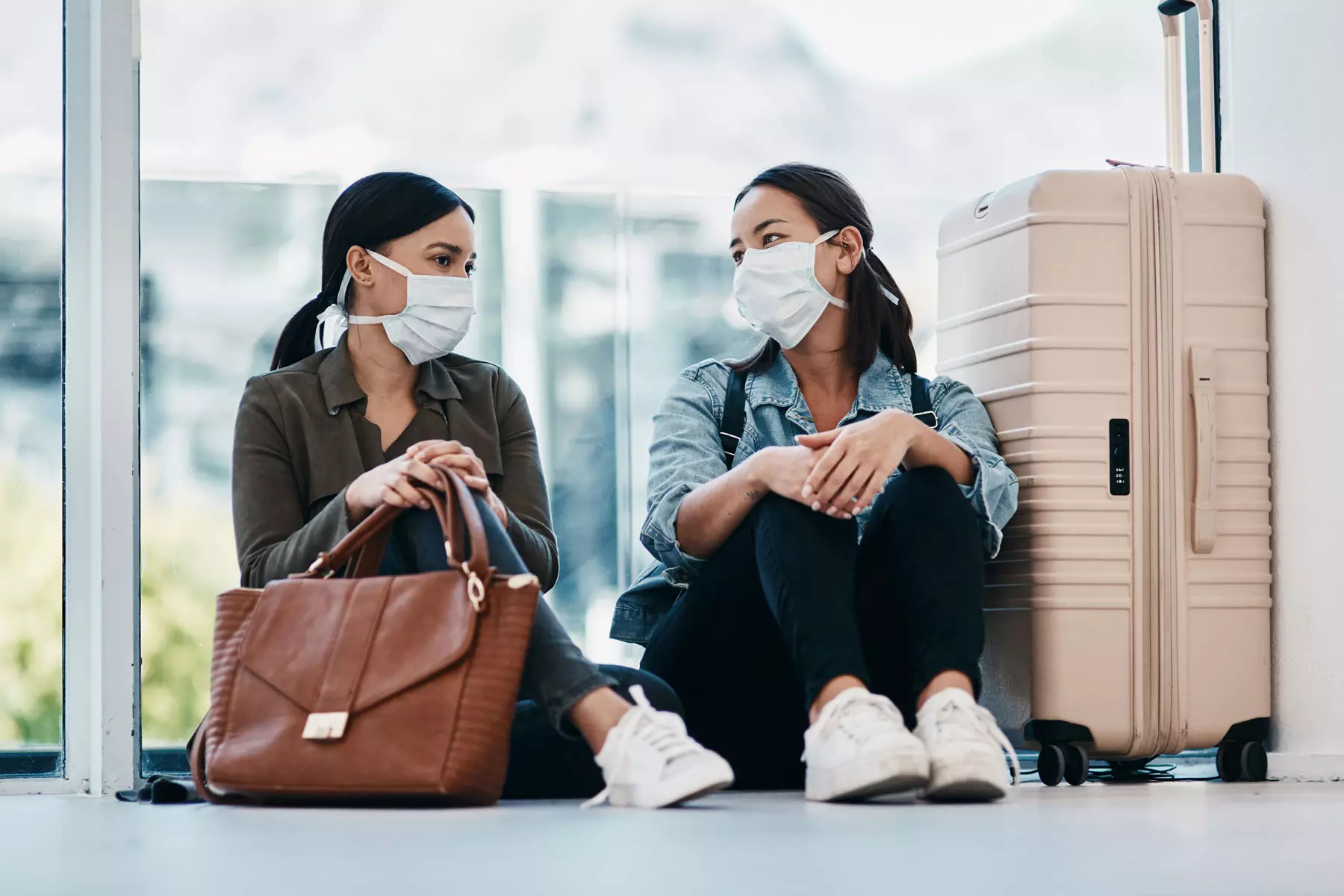 dos personas con máscaras y conversando en el aeropuerto