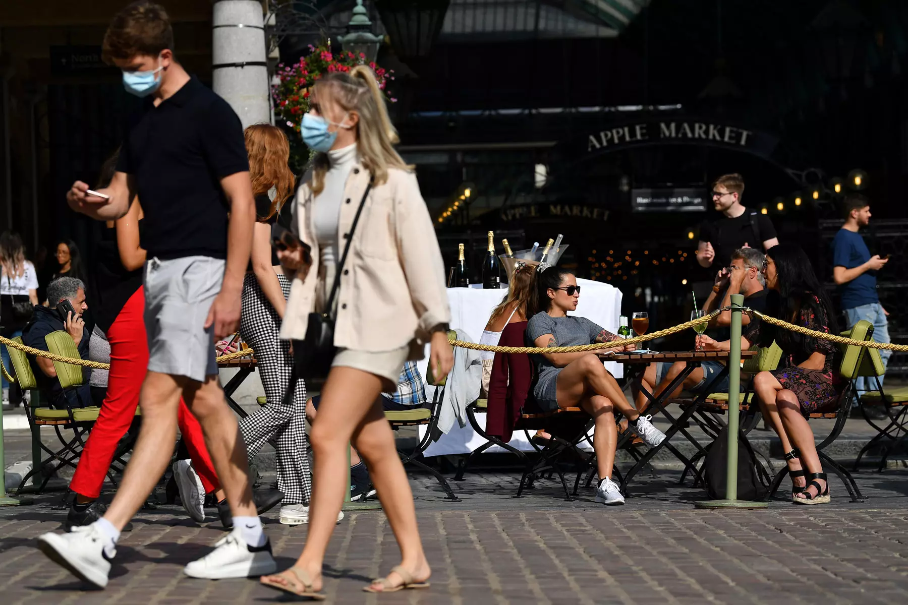 pešci hodijo mimo restavracij na prostem v Londonu