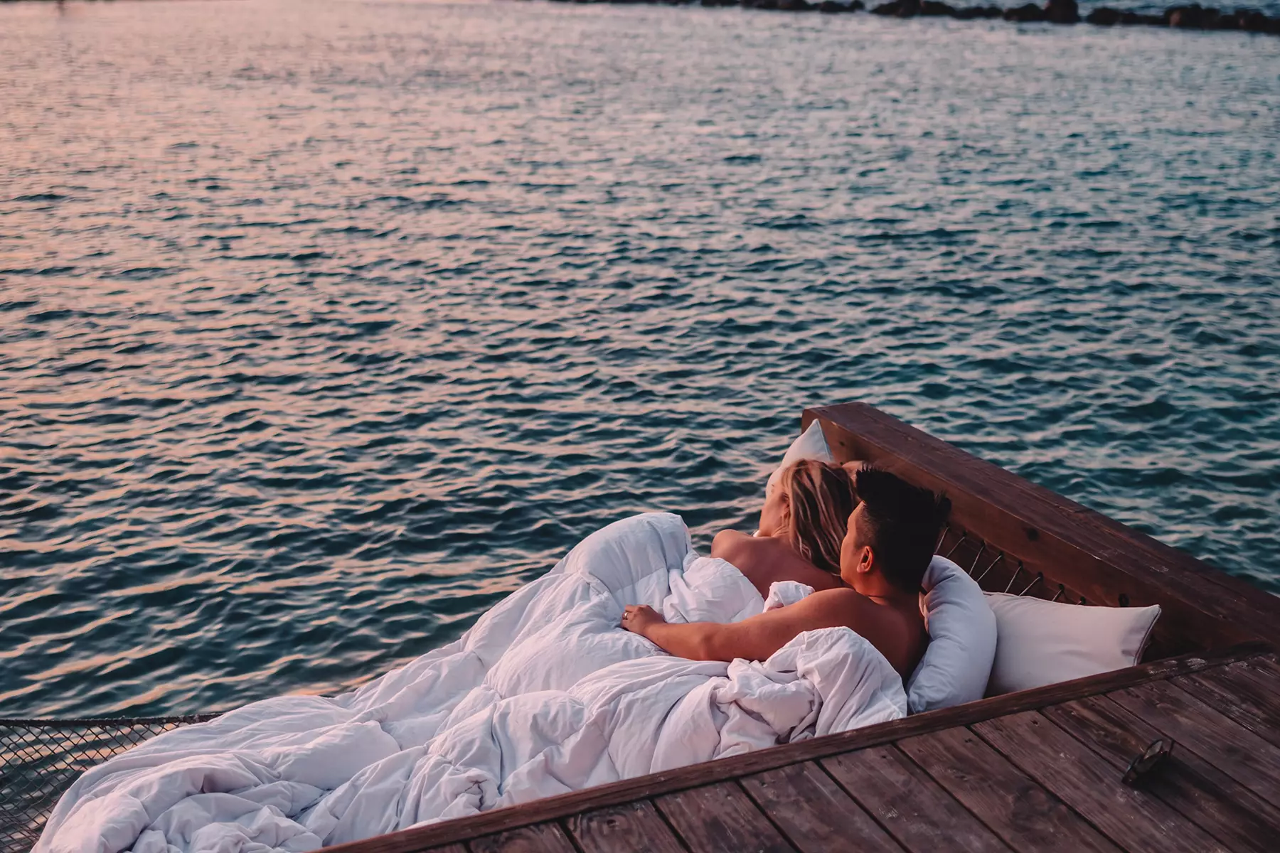 Ein Paar, das in einem Überwasserbett im Renaissance Wind Creek Aruba Resort liegt