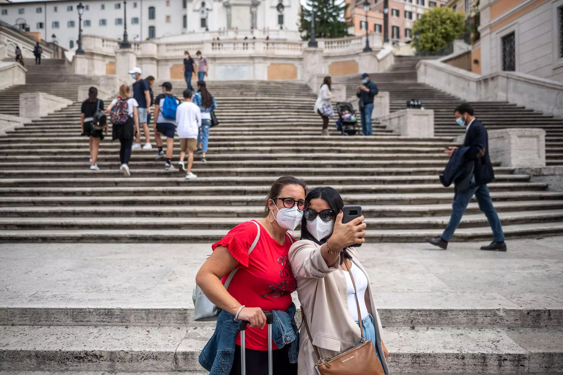 Pessoas usando máscaras de proteção tiram uma selfie na Piazza di Spagna