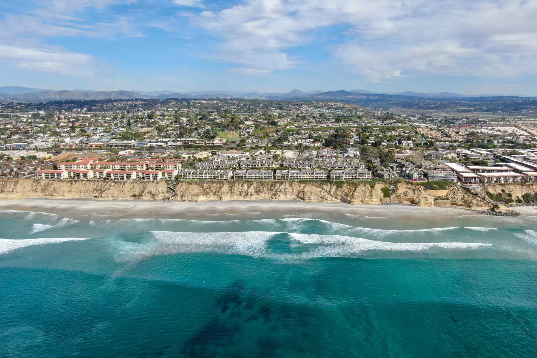 Luftfoto af lejlighedssamfund ved siden af stranden og havet i det sydlige Californien