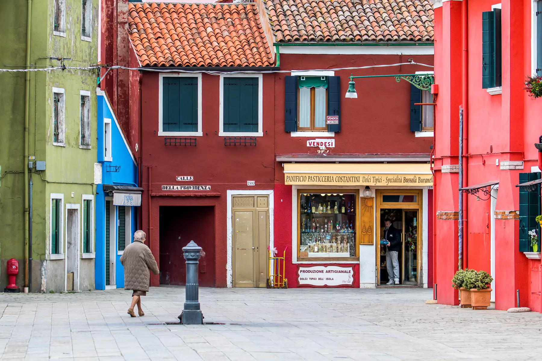 Mujer camina a las tiendas en Burano