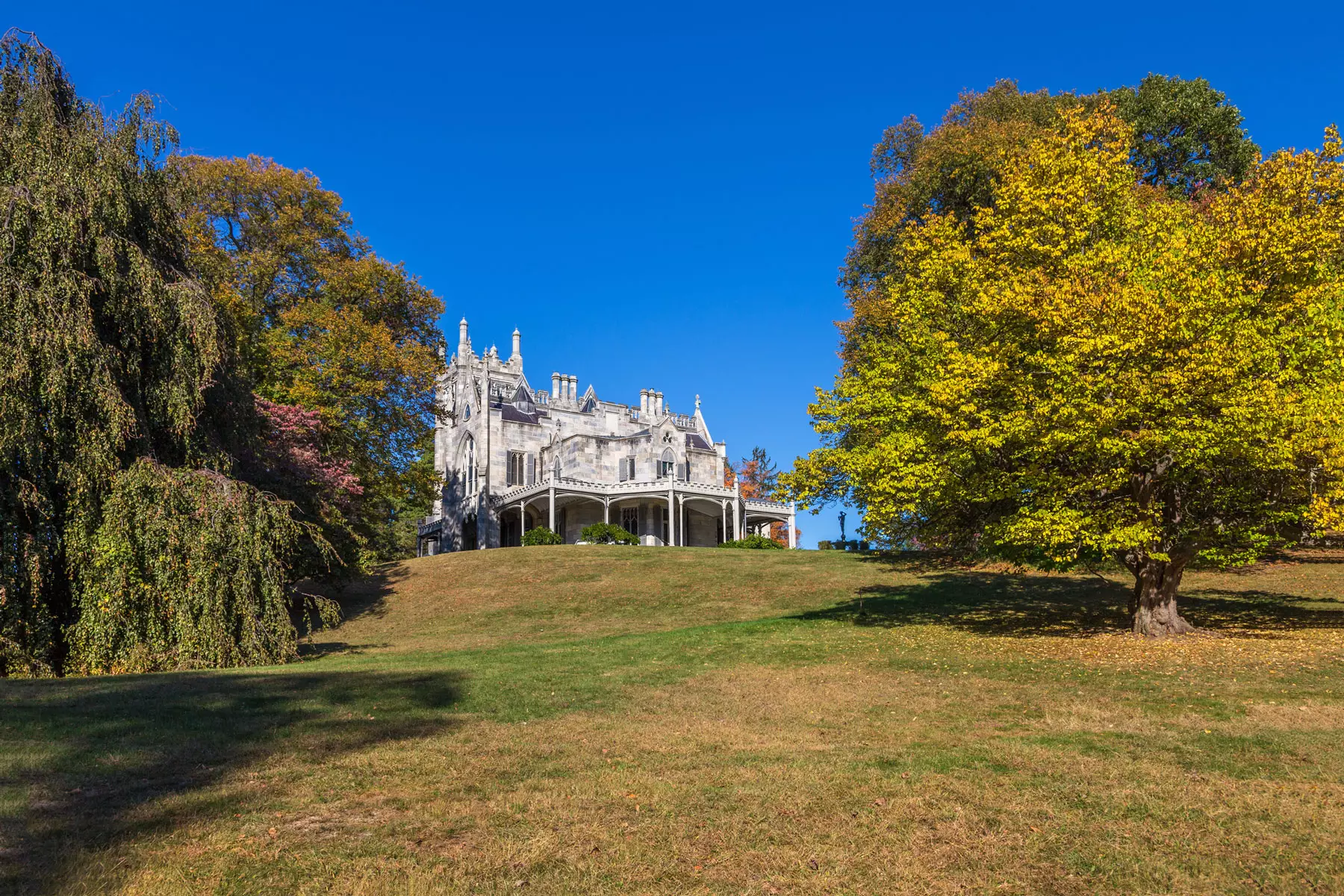 عمارت Lyndhurst، آسمان آبی و درختان در رنگ های پاییزی (شاخ و برگ) در Tarrytown، Hudson Valley، نیویورک.