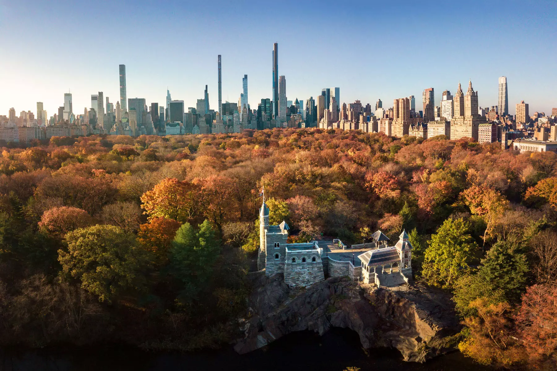 Lanskap Central Park dan Kastil Belvedere dengan cakrawala Kota New York antara Upper West dan Upper East Sides Manhattan di tampilan udara Amerika Serikat. Pemandangan musim gugur dengan dedaunan musim gugur oranye