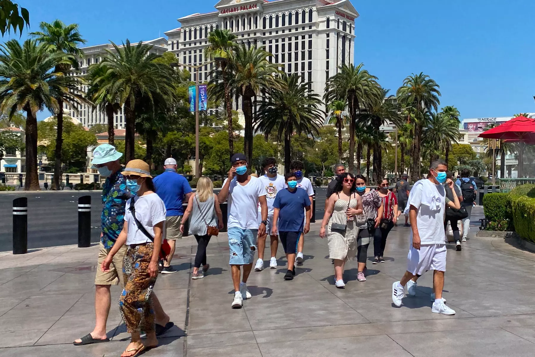 Turis mengenakan topeng berjalan di Strip di Las Vegas