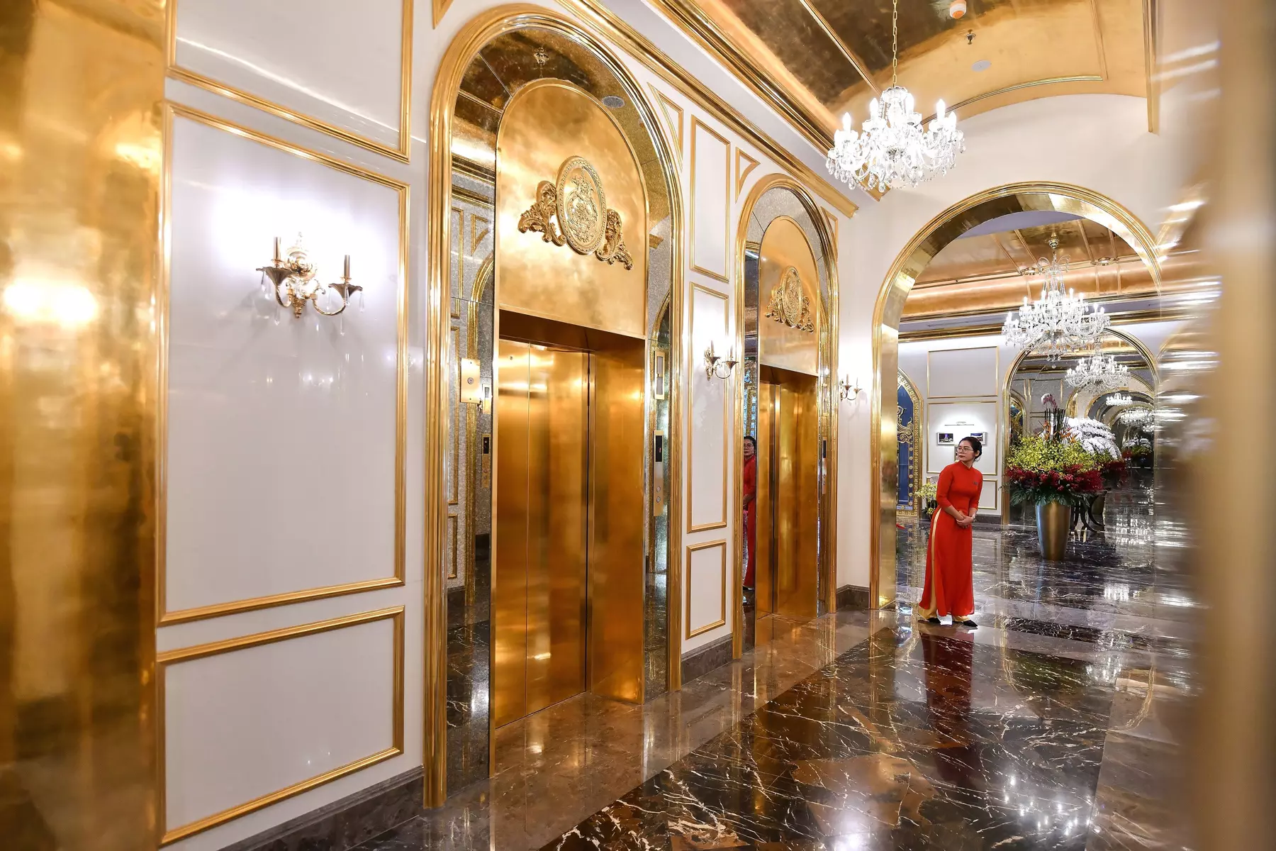 Seorang anggota staf berdiri di dekat lift di lobi hotel Dolce Hanoi Golden Lake yang baru diresmikan, hotel berlapis emas pertama di dunia, di Hanoi pada 2 Juli 2020.