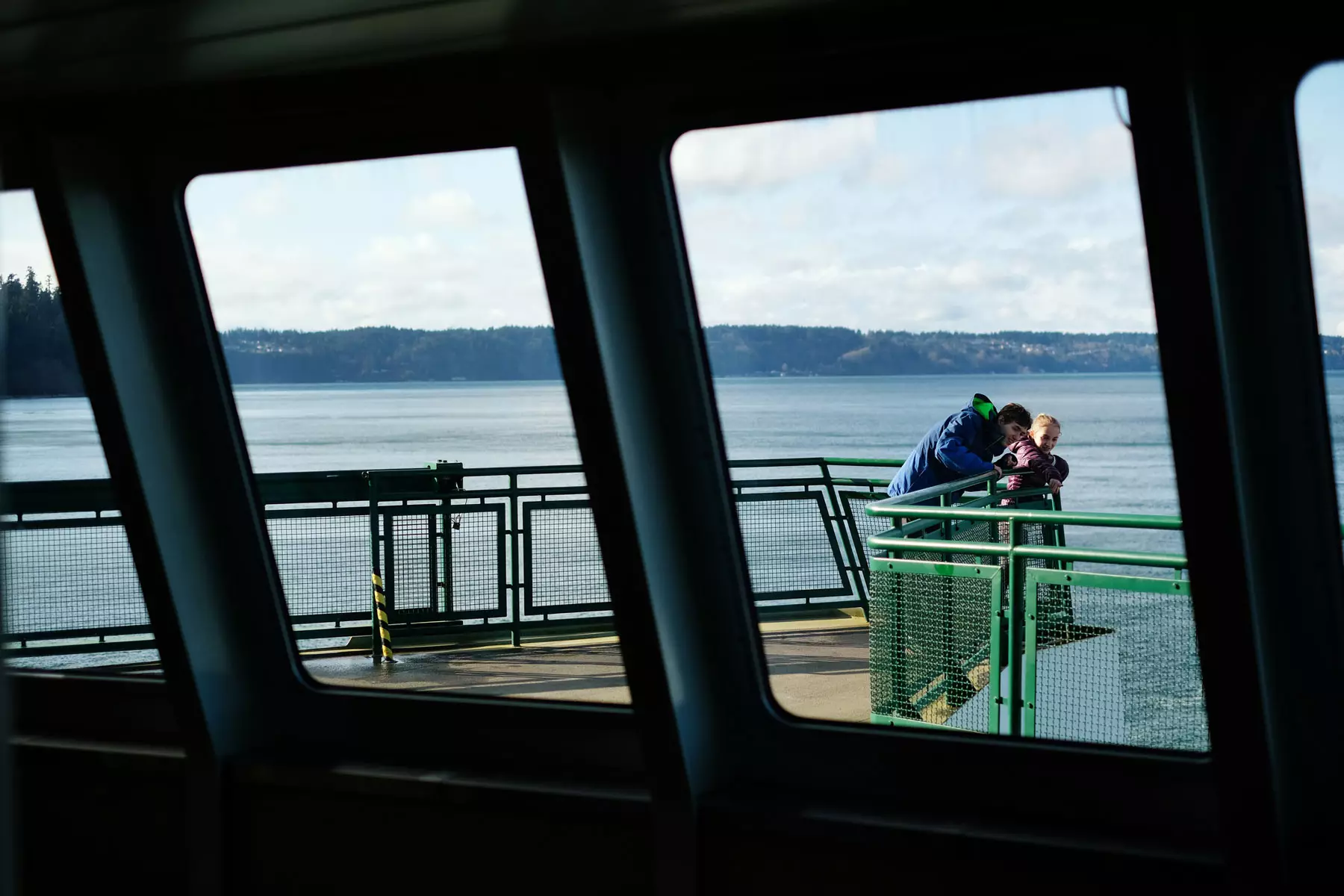 เด็กวัยรุ่นและน้องสาวของเขามองข้ามราวบันไดของเรือข้ามฟากที่เคลื่อนผ่าน Puget Sound ไปยังเกาะ Vashon ในเขต Seattle Washington