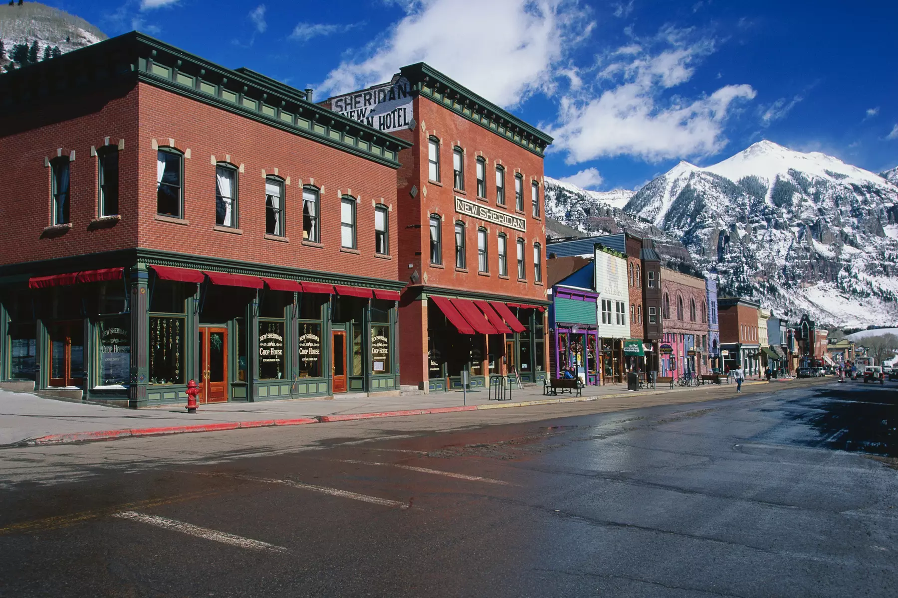 Galvenā iela Telluride, Kolorādo ar veikalu skatlogiem un kalnu tālumā