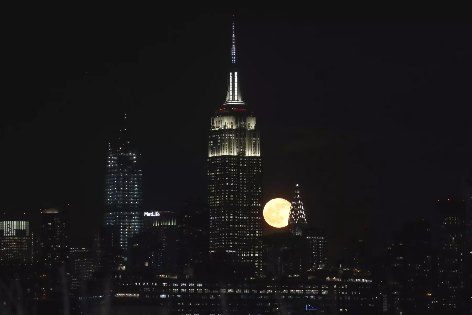 Cold Moon wathunthu ukutuluka kuseri kwa Empire State Building ndi Chrysler Building ku New York City pa Disembala 12, 2019 monga tawonera ku Jersey City, New Jersey.