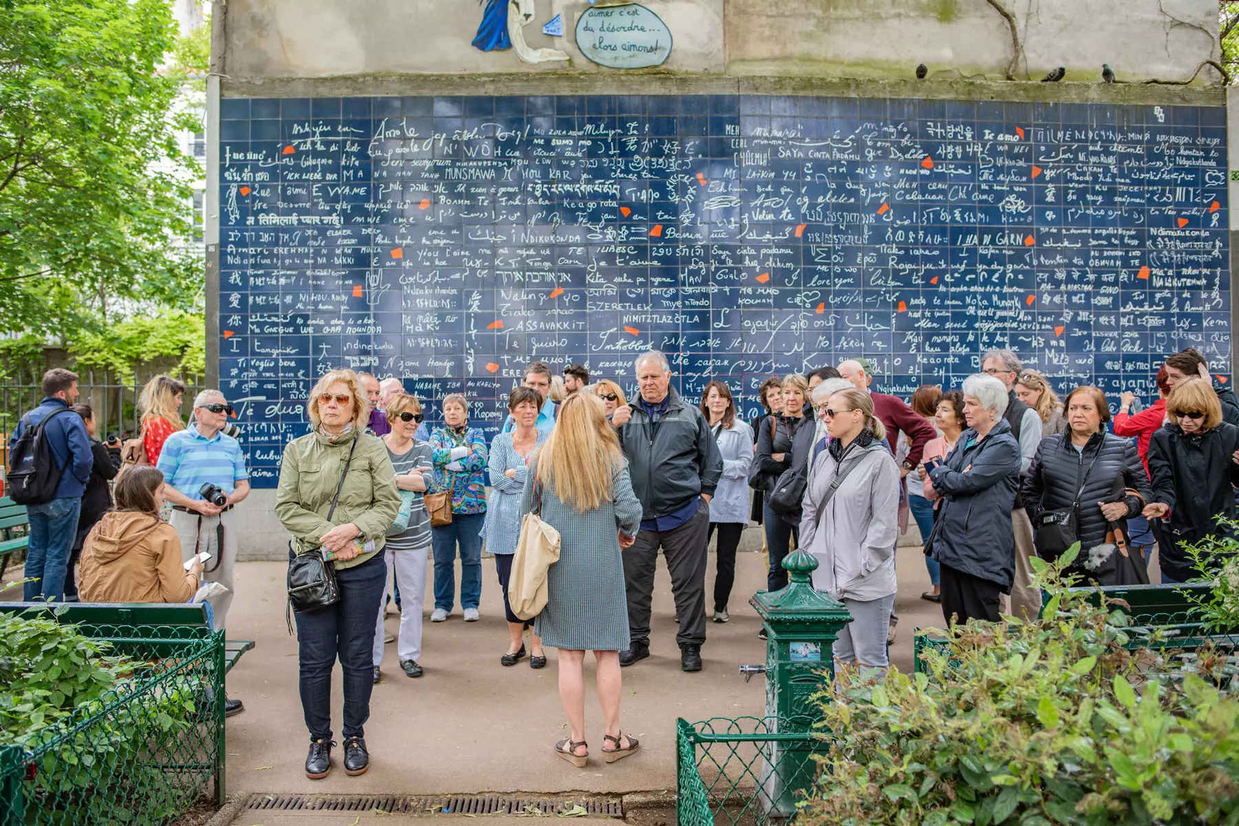 A xente dun gran grupo turístico para para ver o famoso Mural I Love You, unha popular atracción turística do barrio de Montmartre.