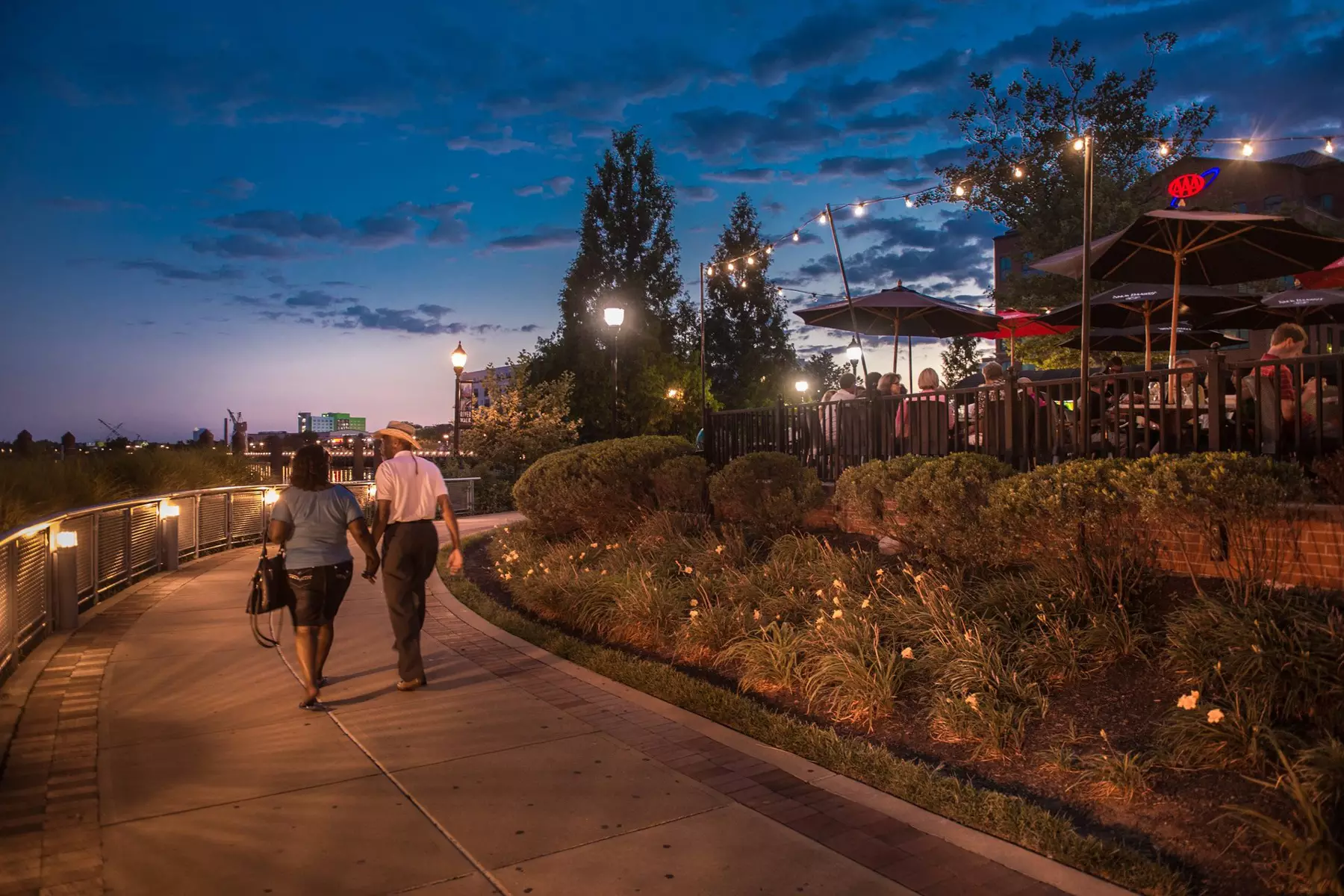 Riverfront walkway na may magkahawak-kamay na mag-asawa sa gabi sa Wilmington, Delaware