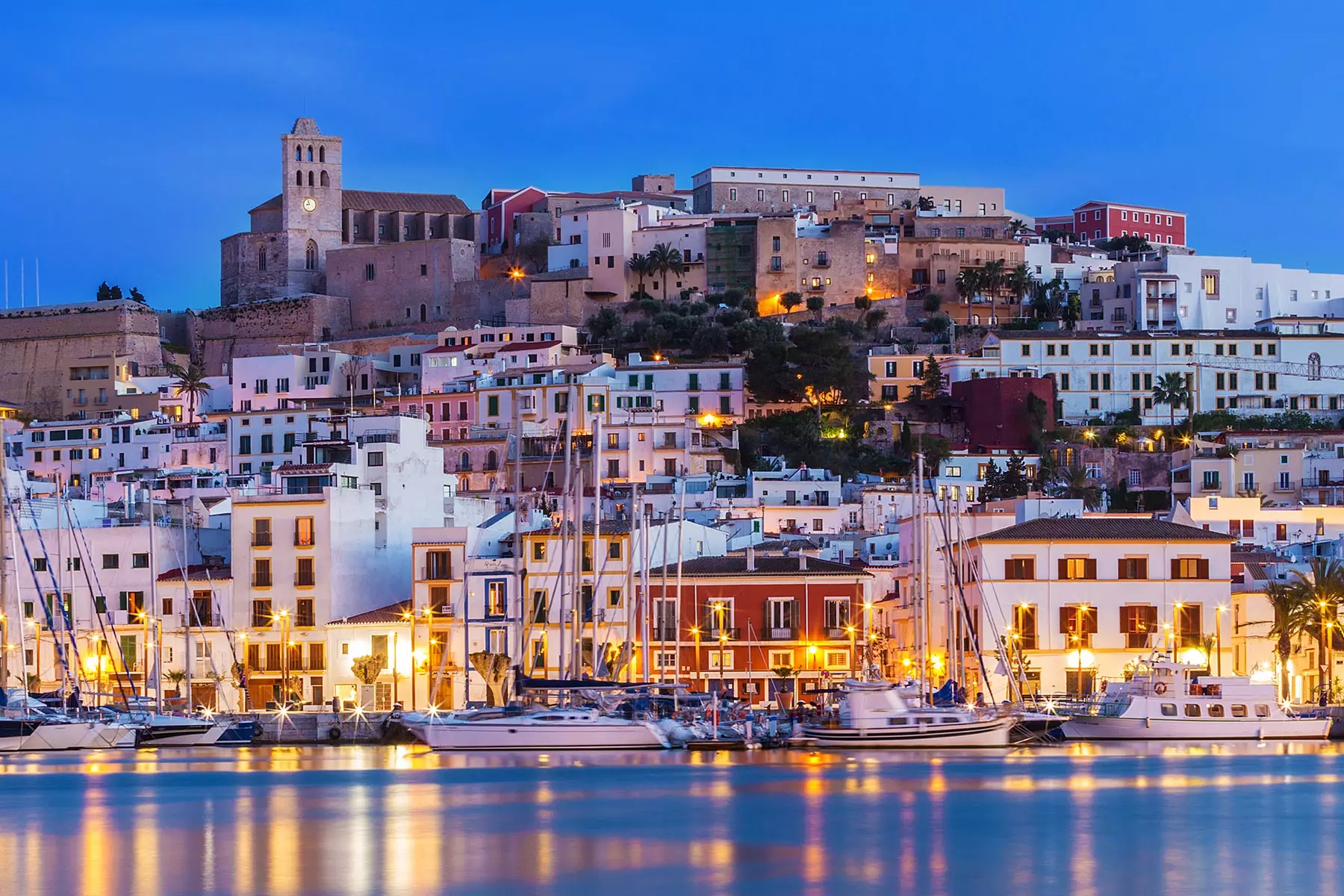 Centro de Ibiza Dalt Vila à noite com reflexos de luz na água, Ibiza, Espanha.