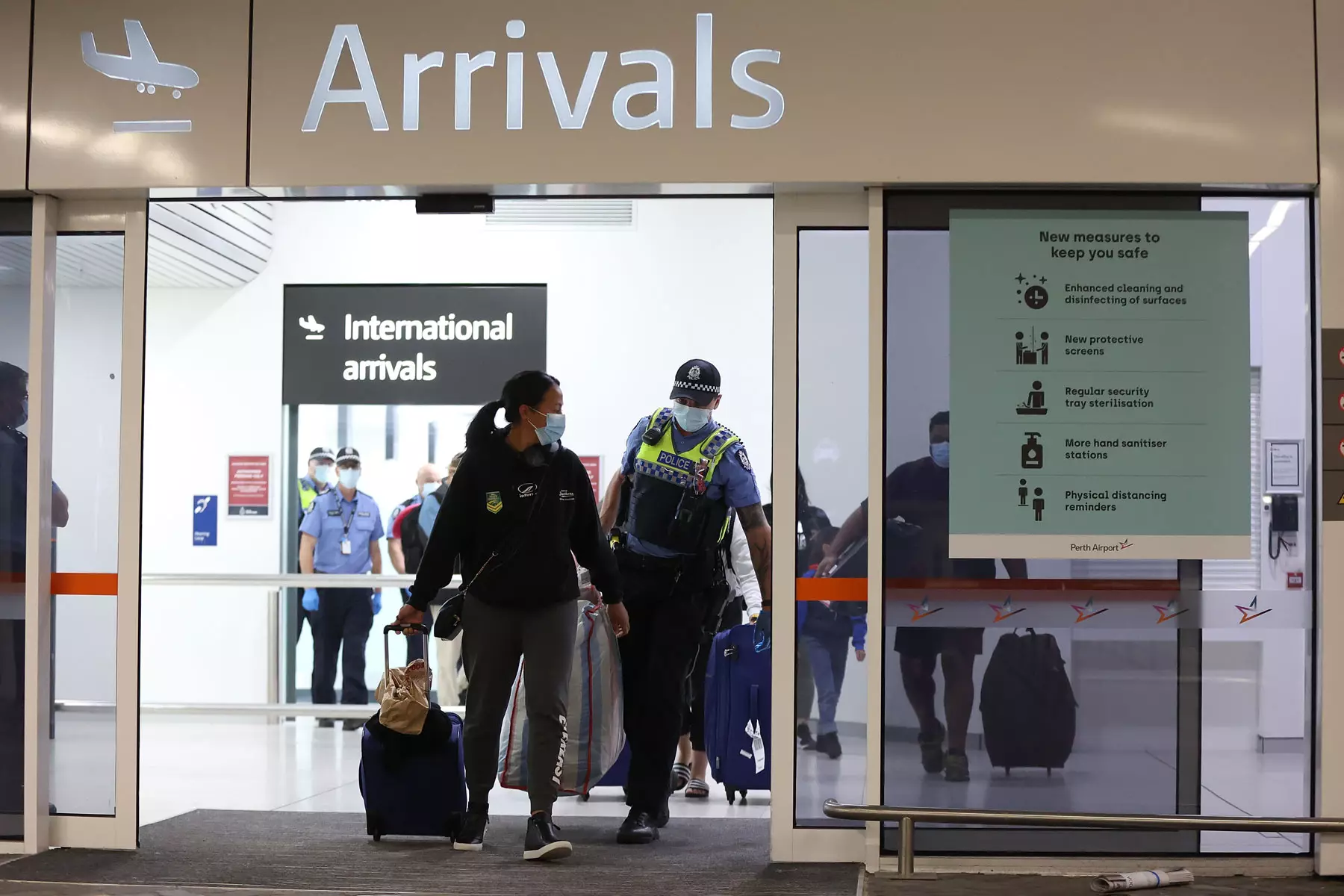 pasajeros en el aeropuerto de Perth siendo escoltados a instalaciones de cuarentena