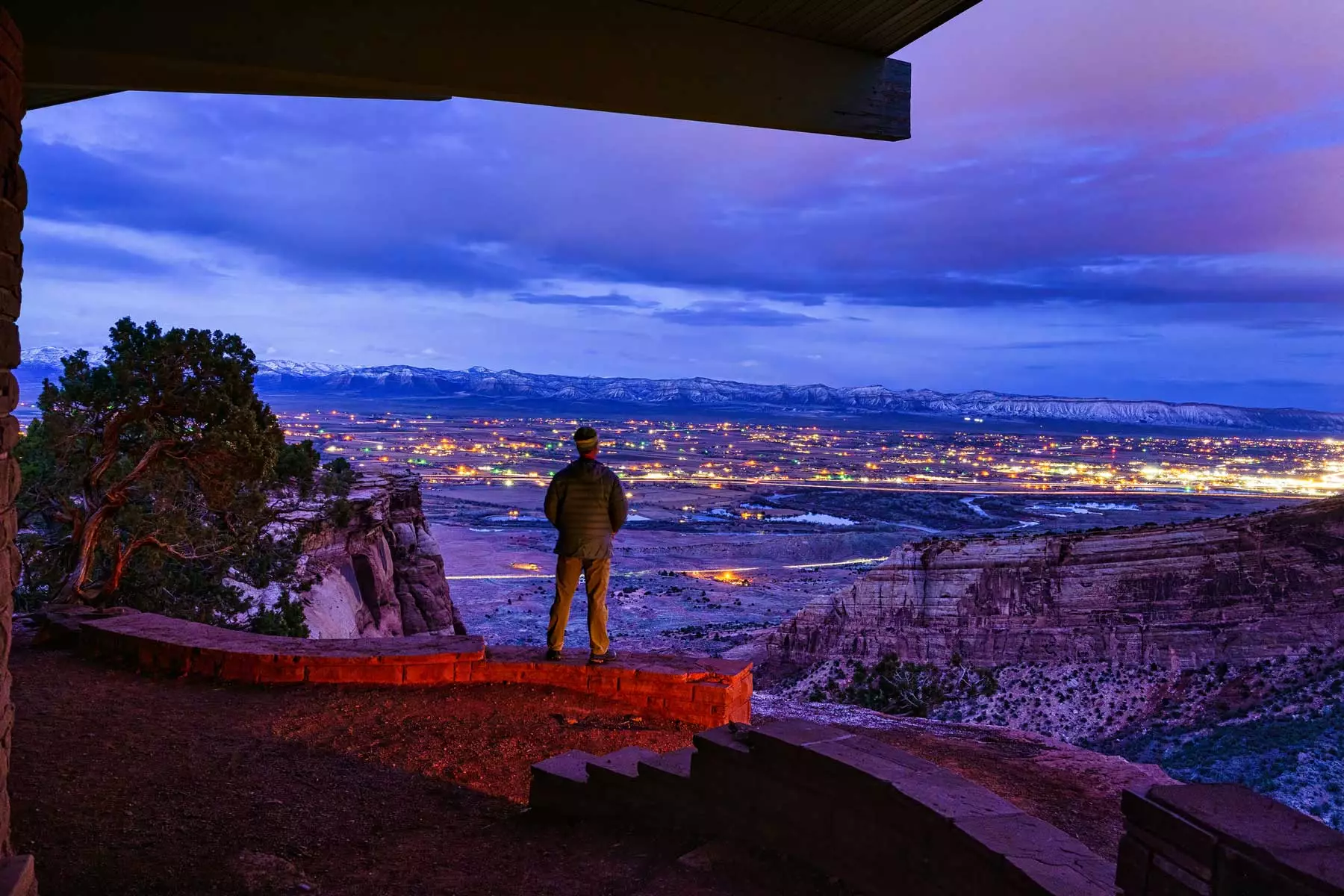 Person, der står på klipper med udsigt over Grand Junction, Colorado om natten