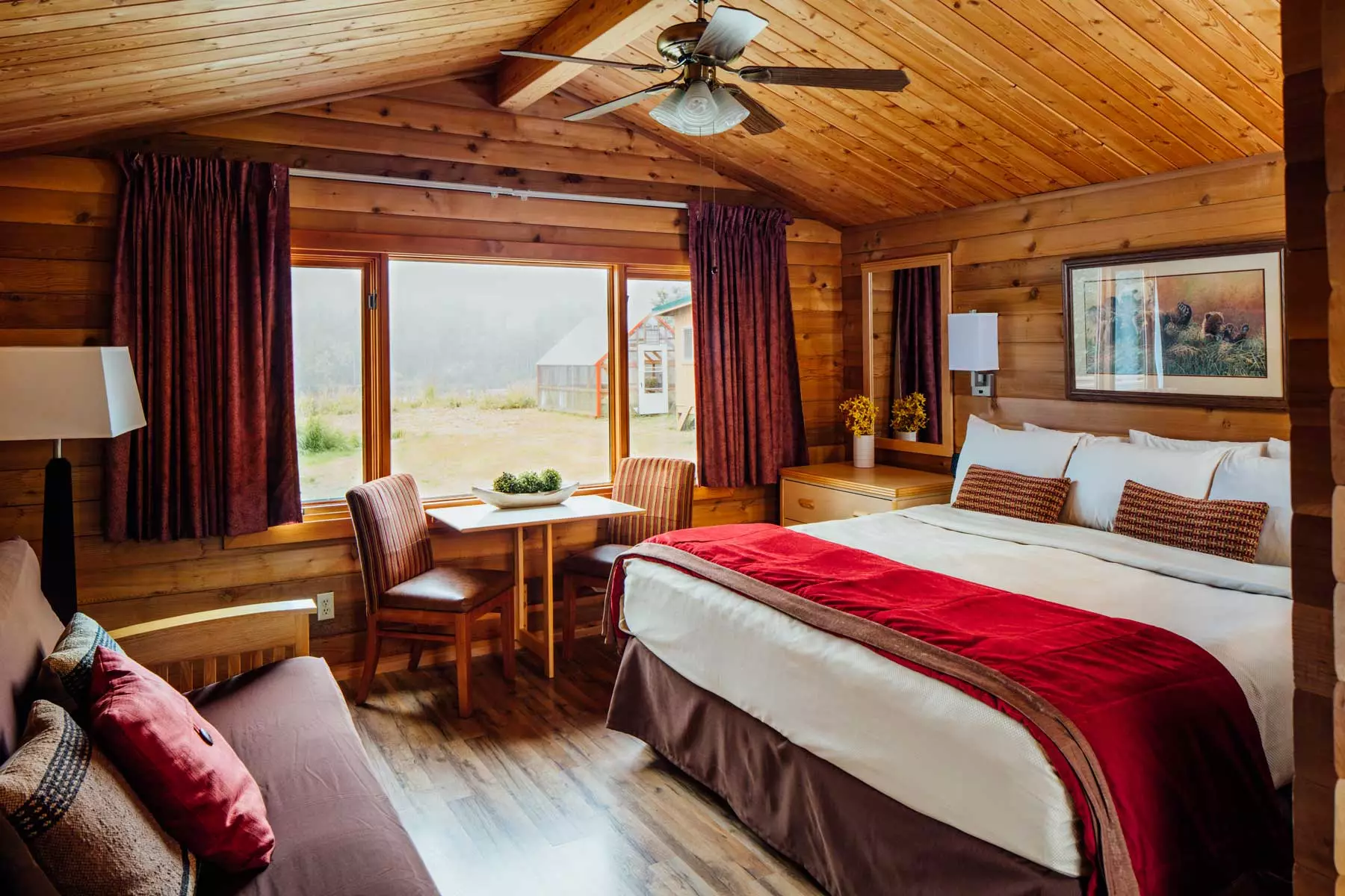 Denali Backcountry Lodge ရှိ အတွင်းခန်း အခန်းသည် ပြတင်းပေါက် မြင်ကွင်းပါရှိသော အိပ်ယာနှင့် ကုလားထိုင်ကို ပြသထားသည်။