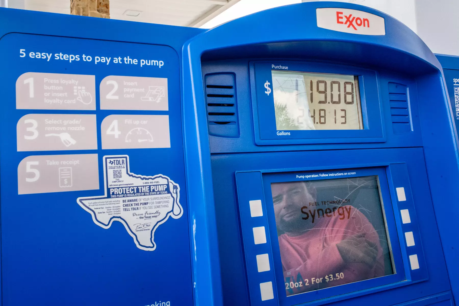 Seorang pelanggan terlihat dalam refleksi melihat kenaikan biaya saat memompa gas