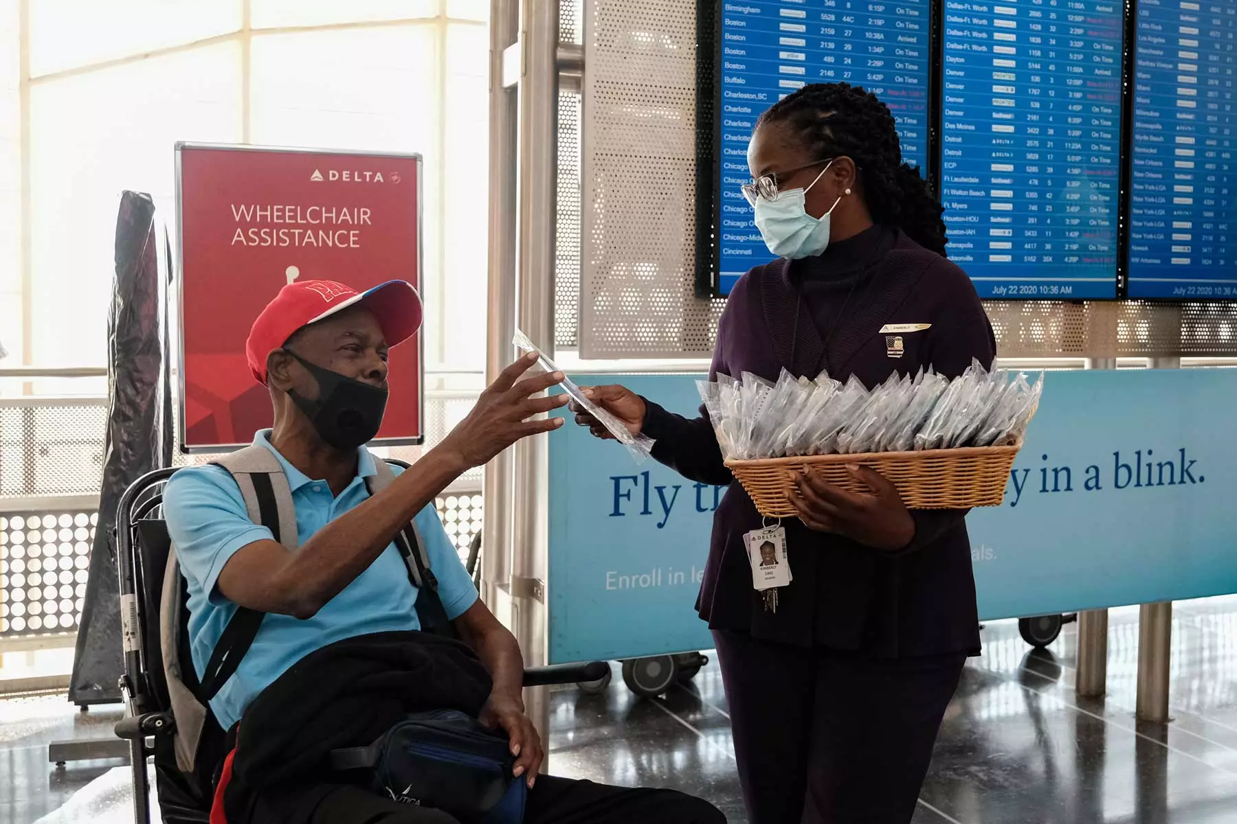 En Delta Airline-ansatt gir en ansiktsmaske til en passasjer under innsjekking på Ronald Reagan National Airport